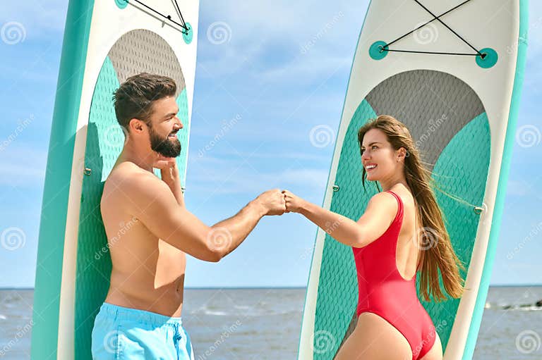 Couple With Surfboards Man And Woman In Swimsuits Doing Fist Bump