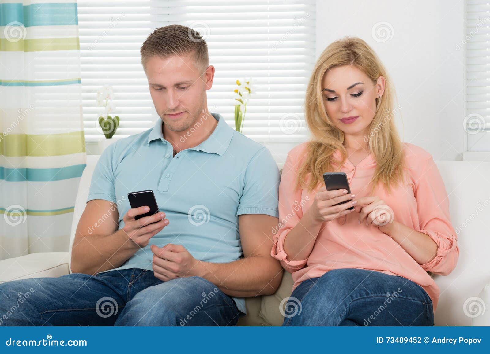 Couple Text Messaging through Mobile Phones on Sofa Stock Photo - Image ...