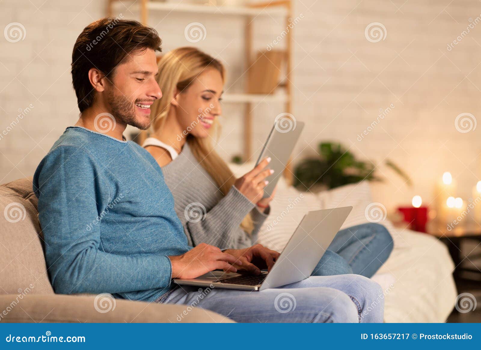 Couple Using Laptop and Tablet Computers Sitting on Couch Indoor Stock ...