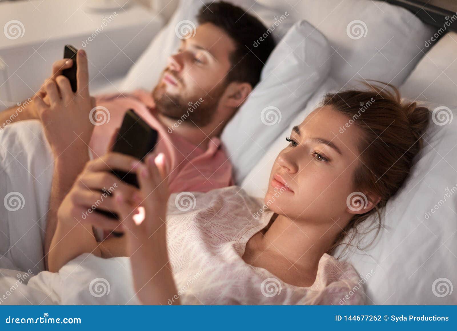 Couple Using Smartphones in Bed at Night Stock Photo - Image of laying ...