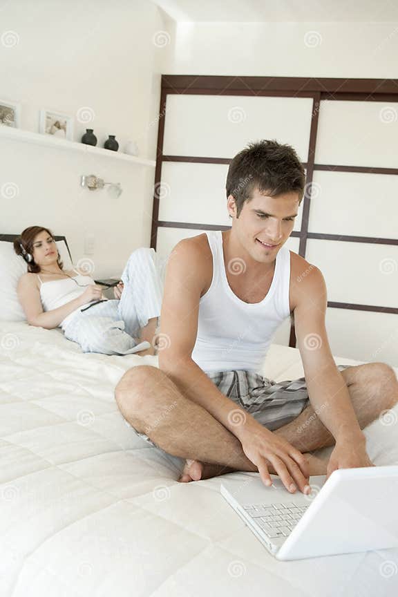 Couple Using Techno on Bed stock image. Image of doors - 24786755