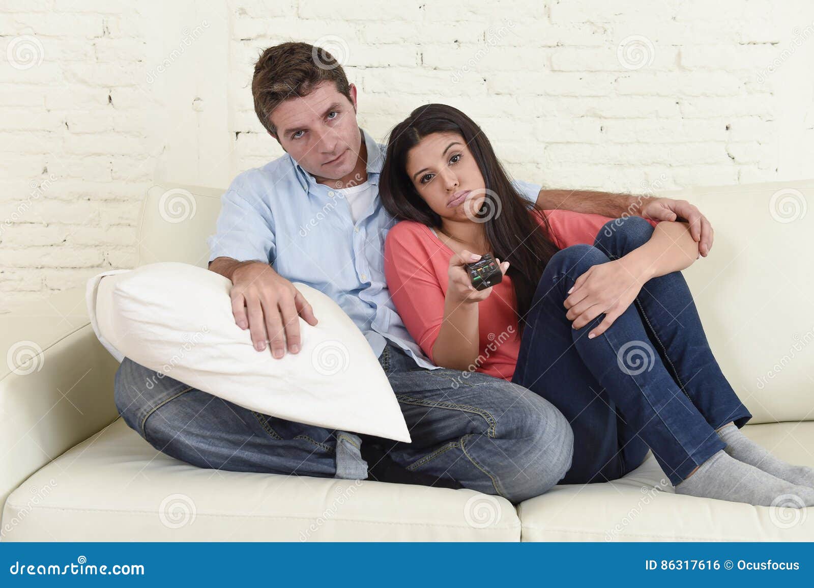Couple Watching Television Together At Home Sofa Couch Looking Bored