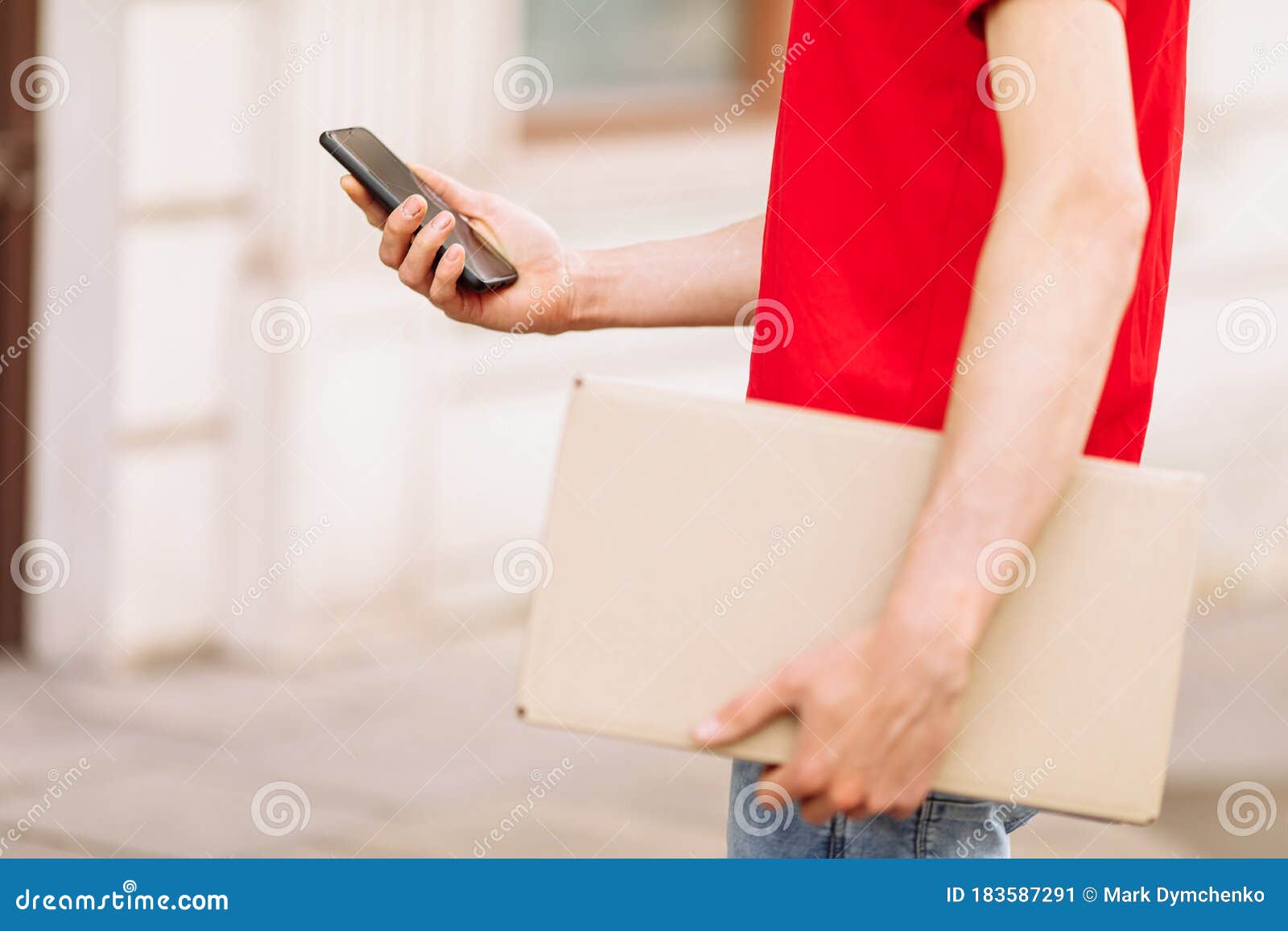 A Courier with a Cardboard Box Using a Mobile Phone. Home Delivery ...