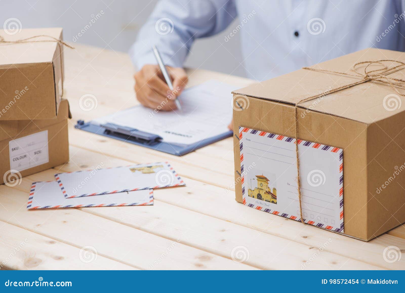 Courier Making Notes in Delivery Receipt among Parcels at Table Stock ...