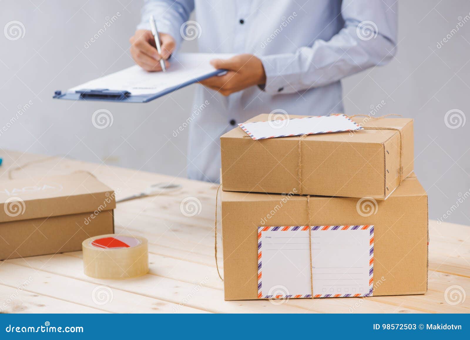 Courier Making Notes In Delivery Receipt Among Parcels At Table Stock ...