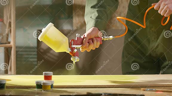A Craftsman Paints a Wooden Board with a Red Paint Gun. Stock Image ... A Craftsman Paints a Wooden Board with a Red Paint Gun. Stock Image ...