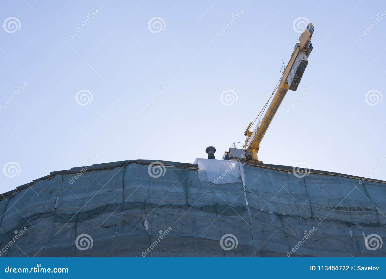 Crane at the Top of the Building Under Construction Covered with a ...