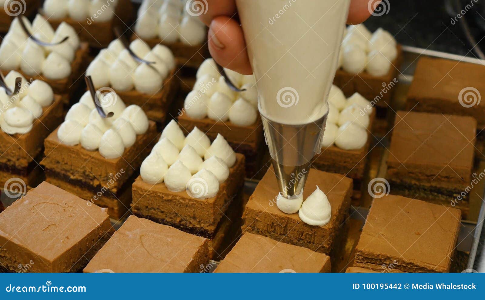Cream Being Squeezed Onto Chocolate Cakes. Squeezing the Cream on the ...