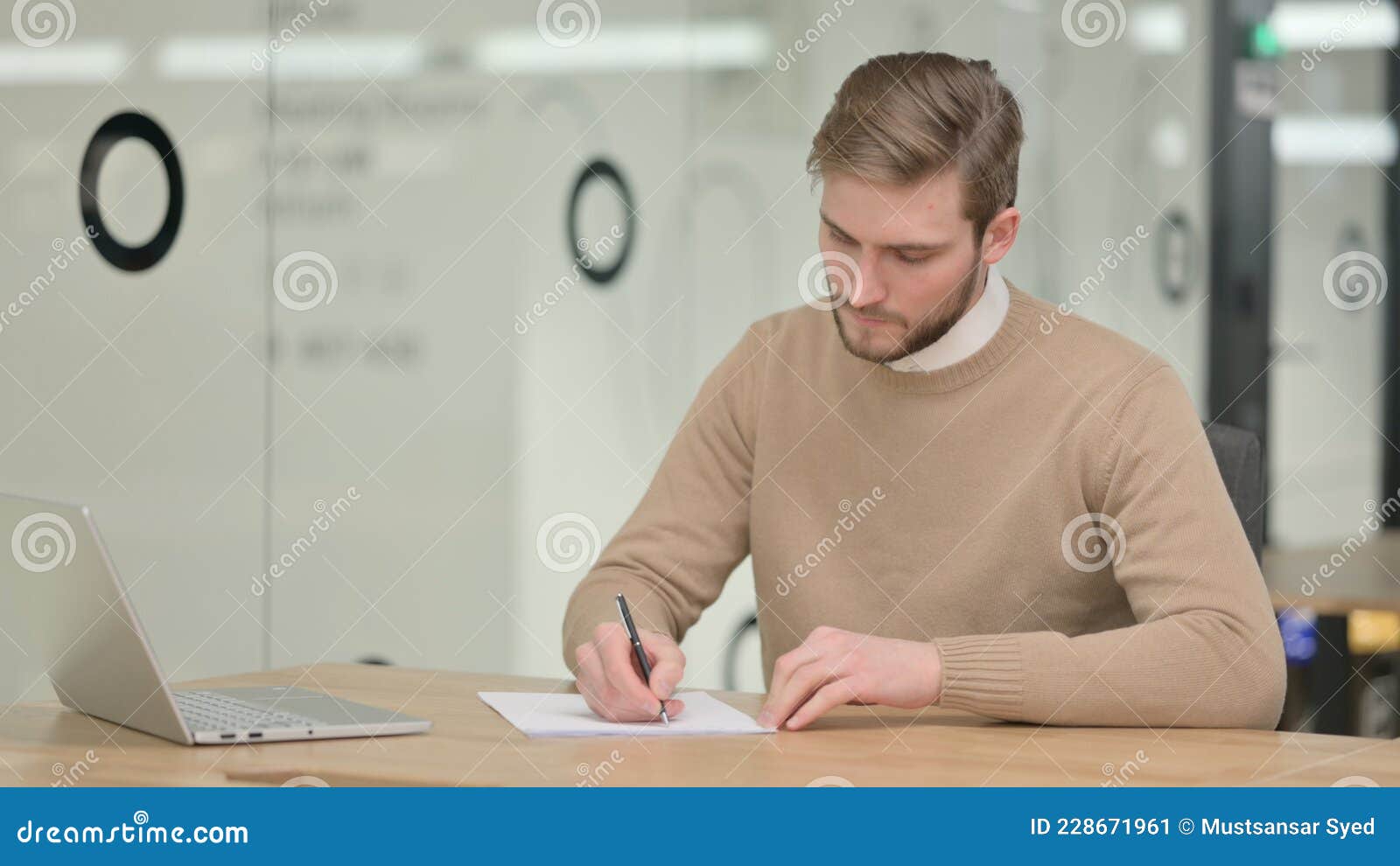 Young Man Writing on Paper in Office Stock Image - Image of book, desk ...