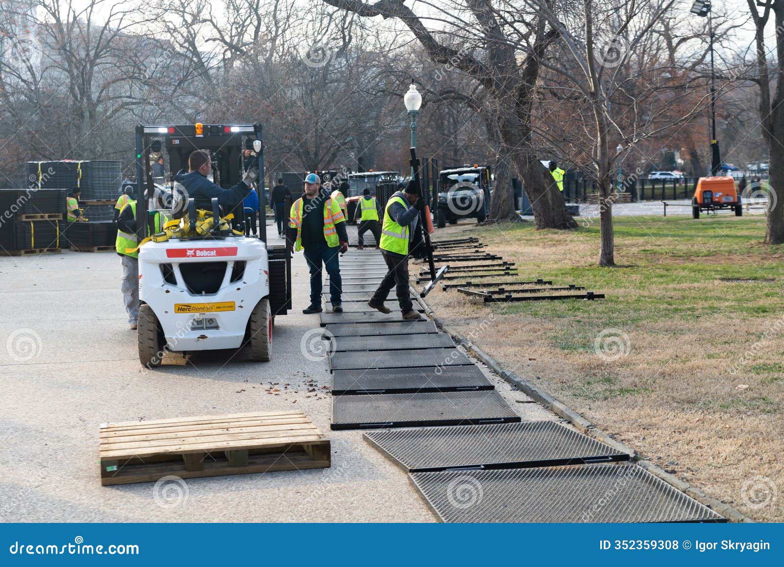 Crew of Workers and a Loader Install Temporary Fencing Outside the ...