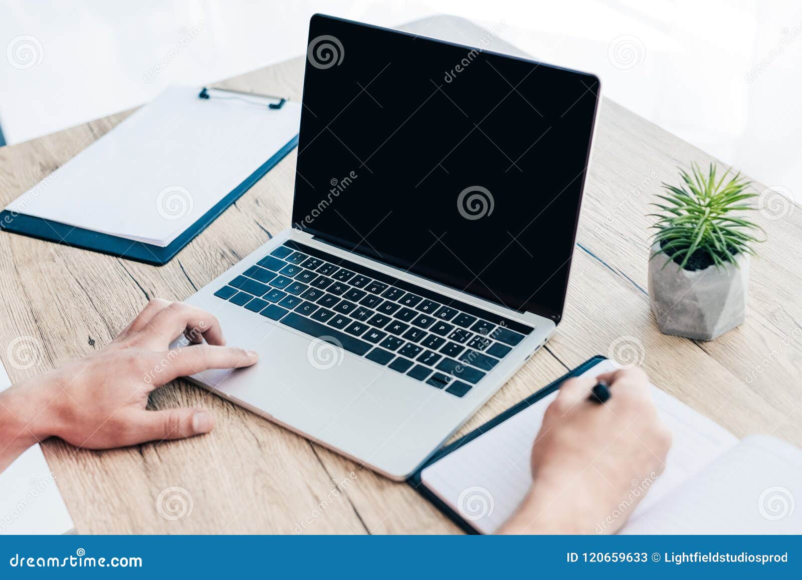 Cropped Image of Man Writing in Textbook and Using Laptop at Table with ...