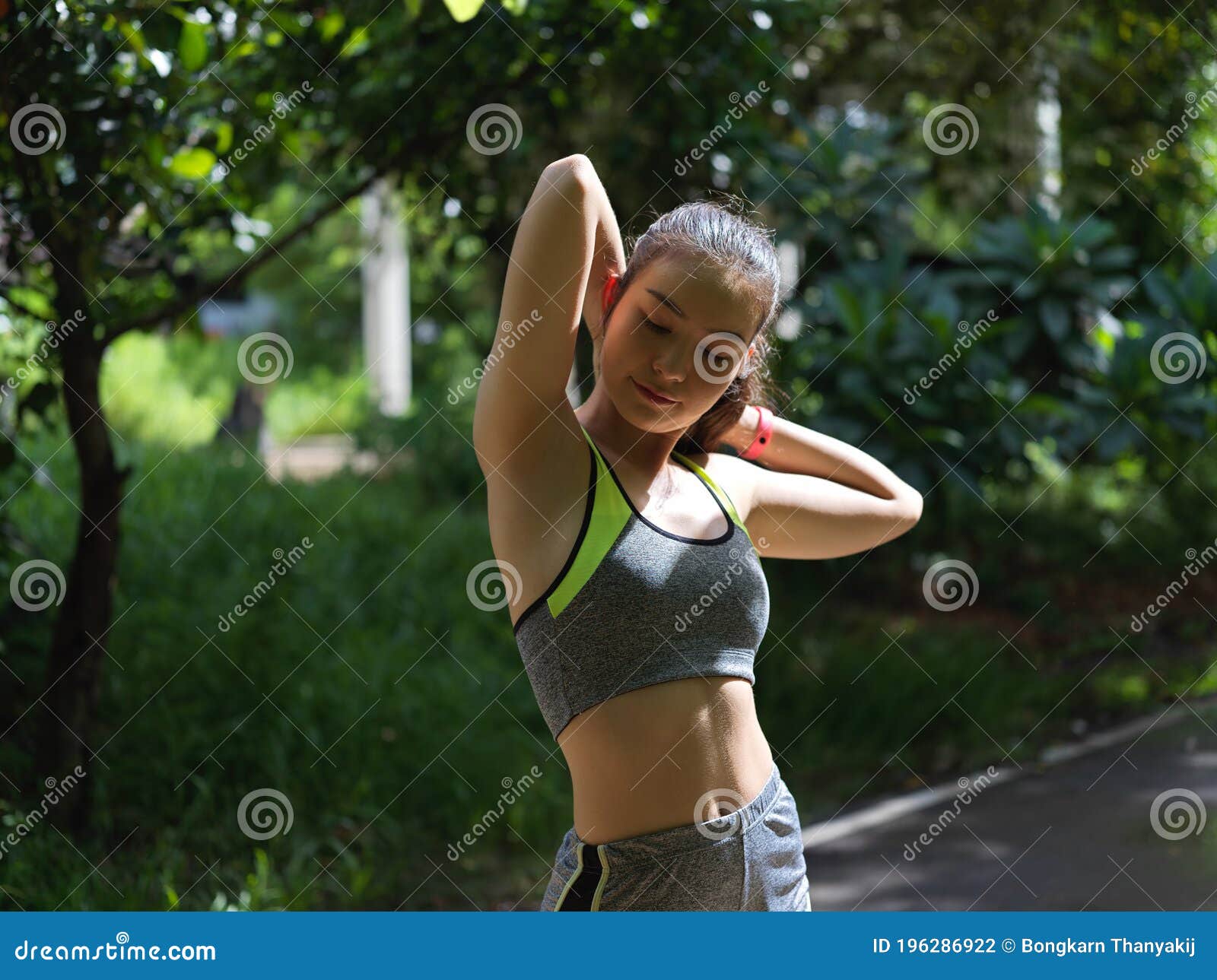 Asian Female Stretching Her Arms Before Exercising In The Park Stock