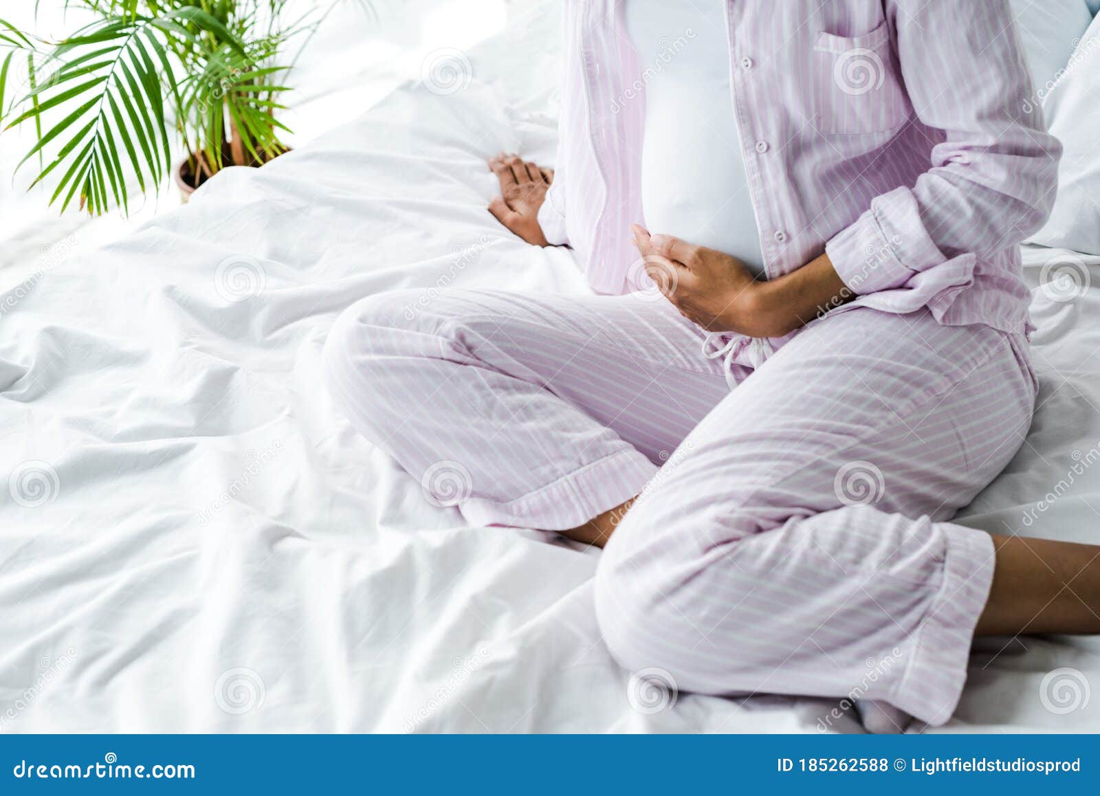 View Of African American Pregnant Woman Touching Belly On Bed Stock