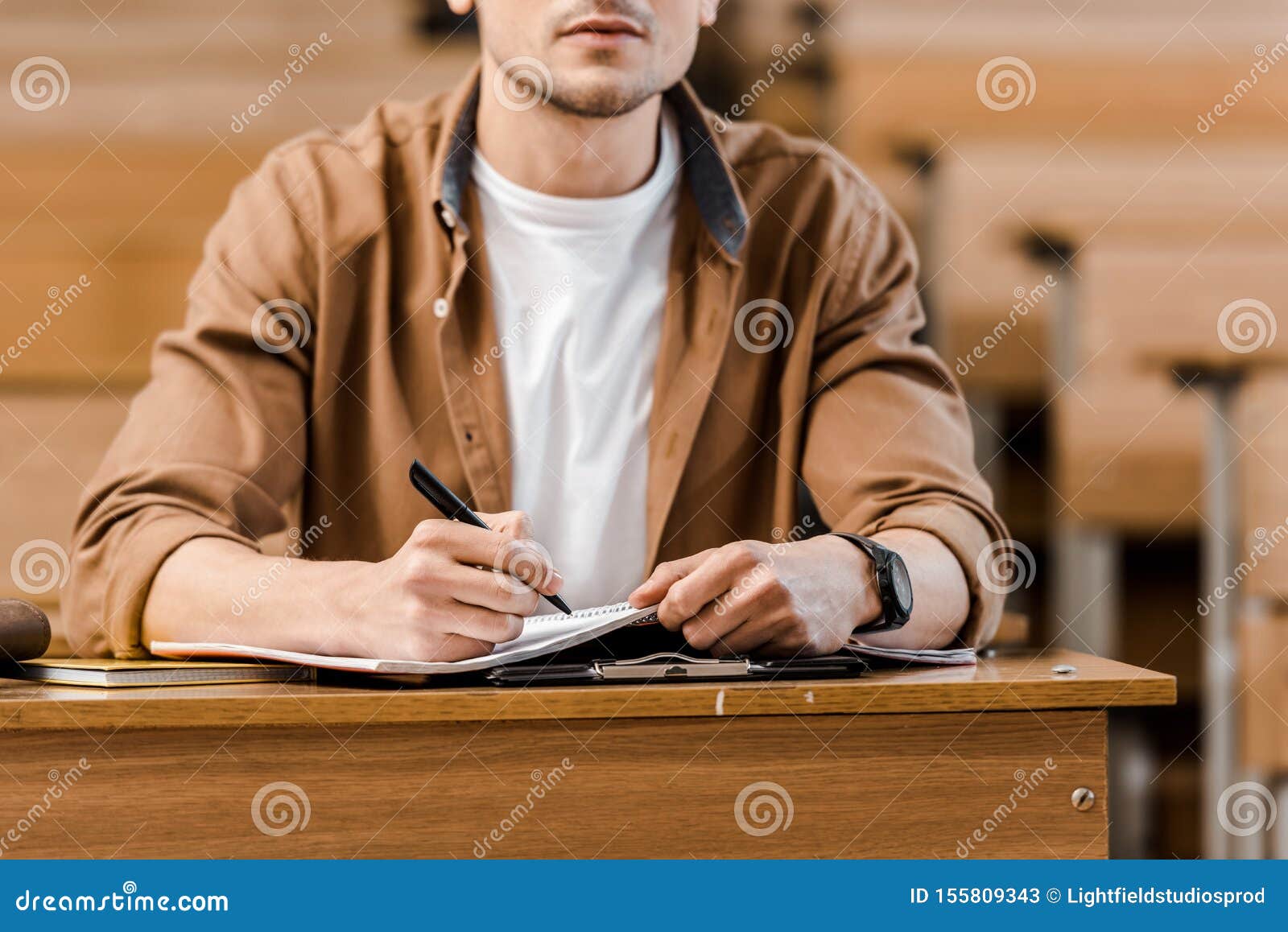 Cropped View of Male Student Sitting at Desk and Writing in Notebook ...