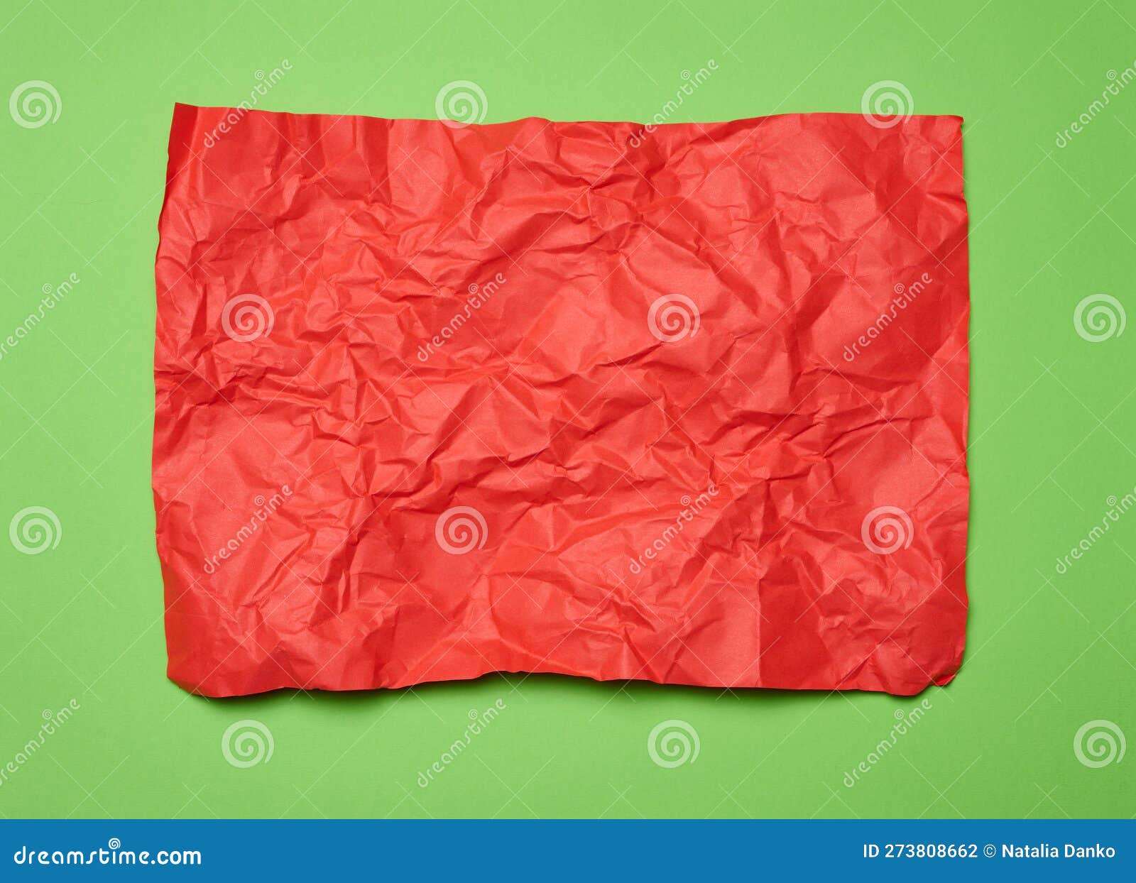 Crumpled Rectangular Sheet of Red Paper on a Green Background, Top View ...