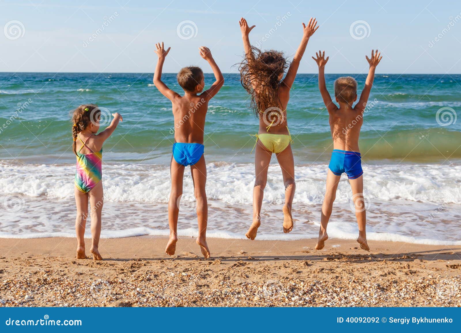 Cuatro Niños Que Saltan En La Playa Foto De Archivo Imagen De Lindo