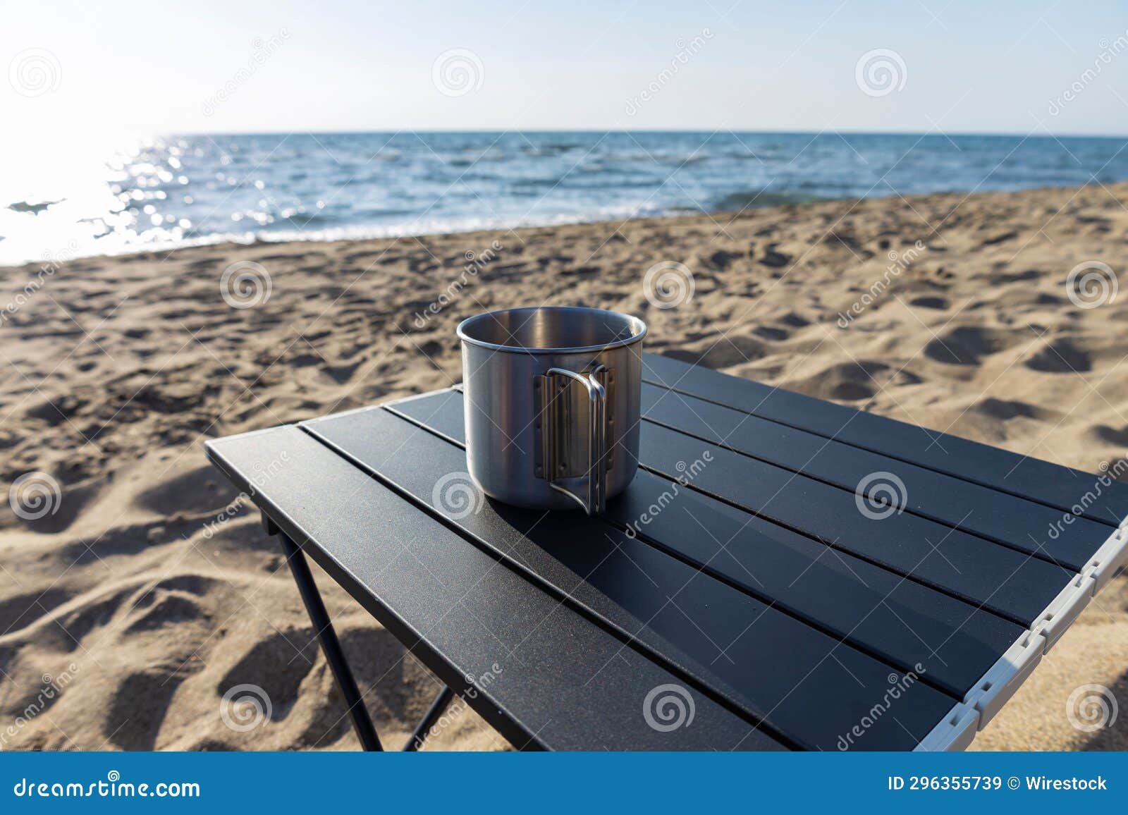 Cup of Coffee Atop of a Table on a Sandy Beach with the Ocean Visible ...