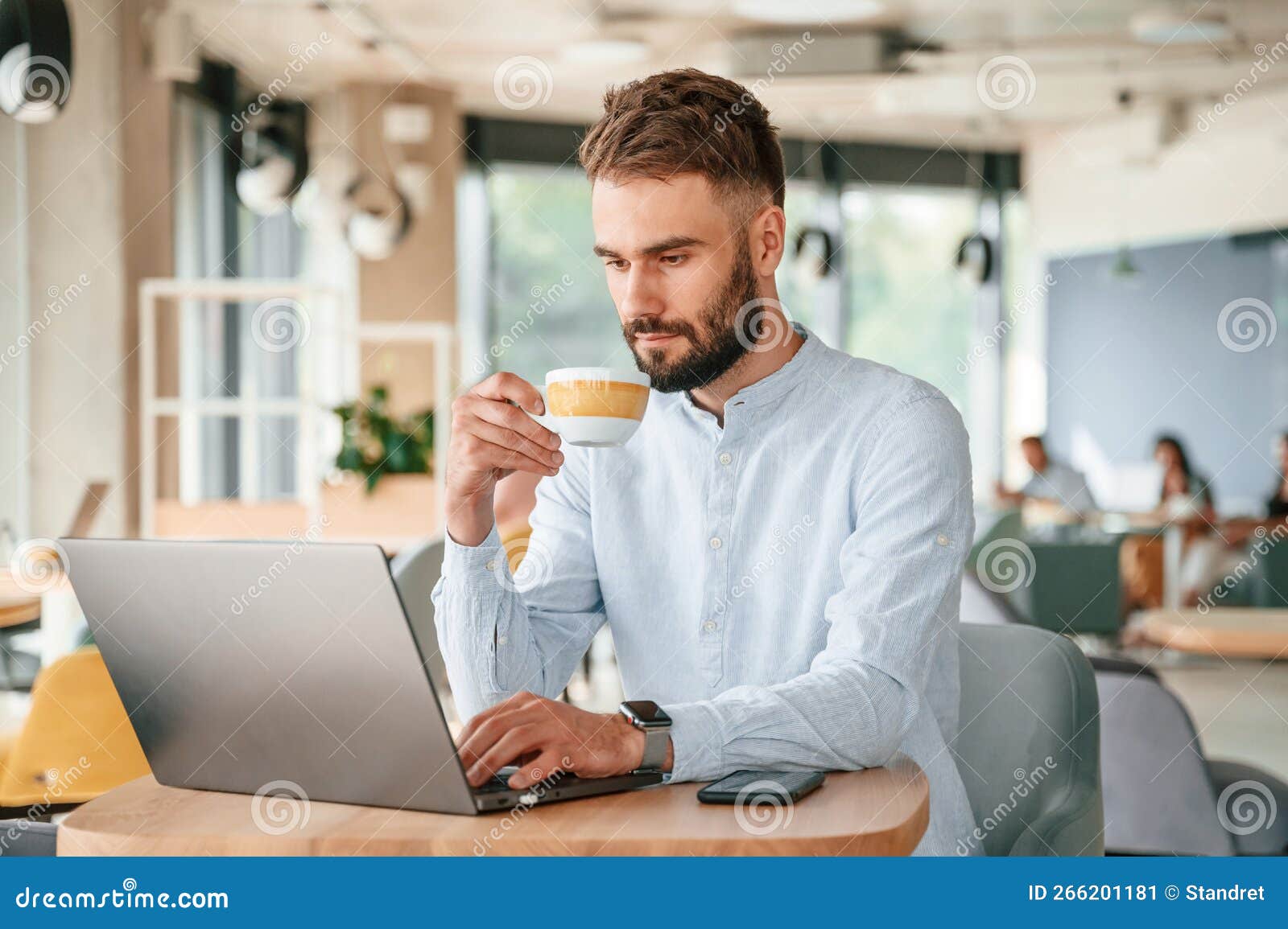 With Cup of Drink. Young Man is Sitting in the Cafe and Working by ...