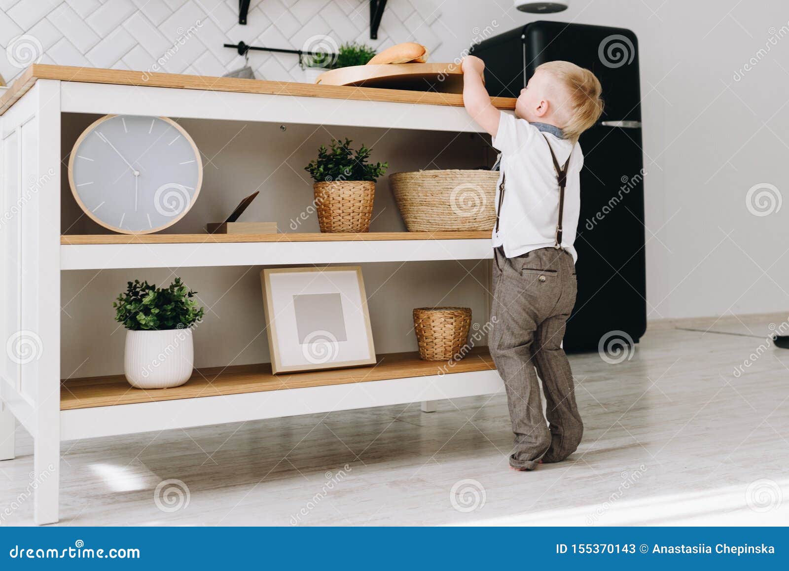 A Curious Little Boy Backside Pulling a Tray with Bread from the Table ...