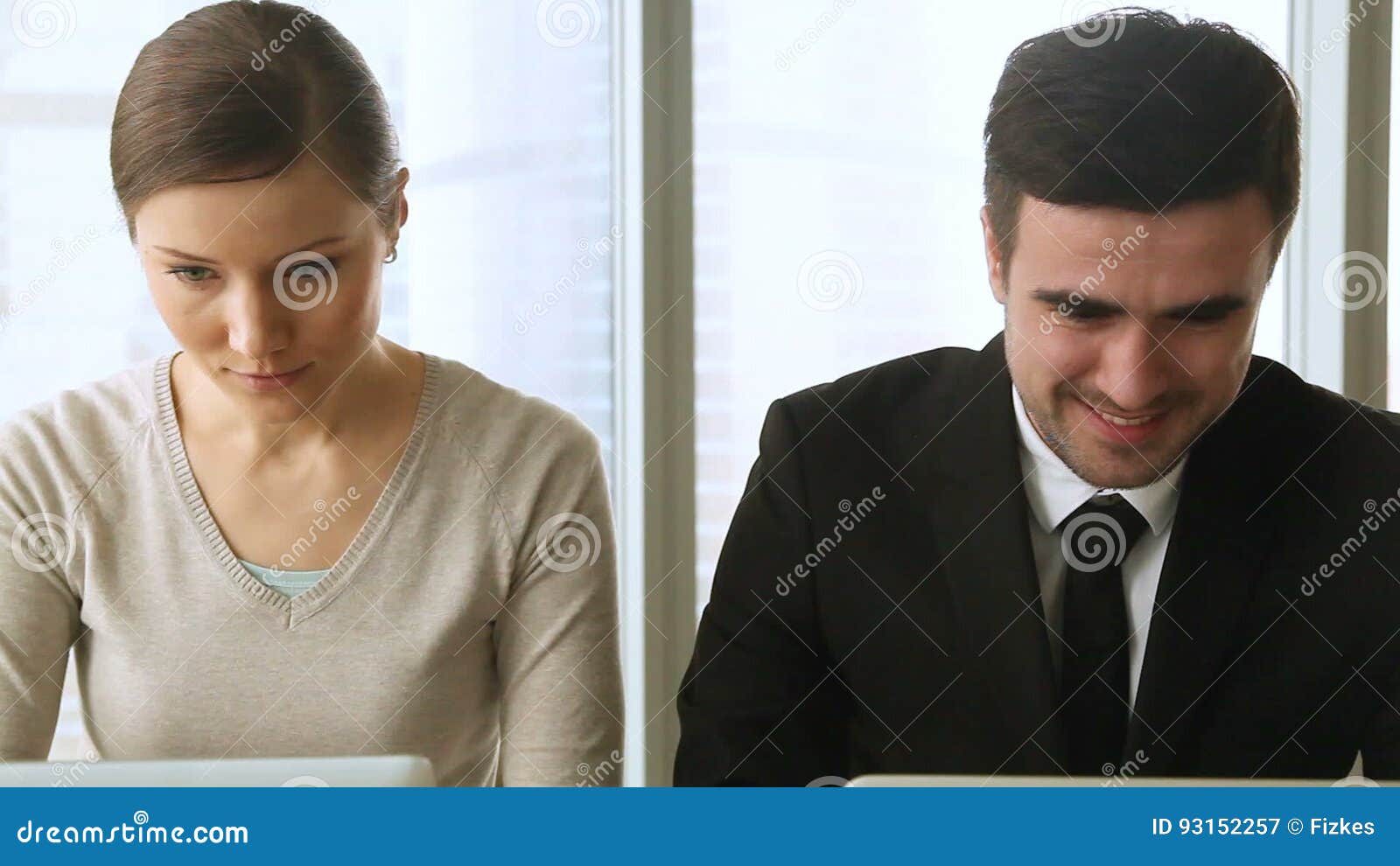 Curious Woman Spying Male Colleague Looking At His Laptop Screen Stock