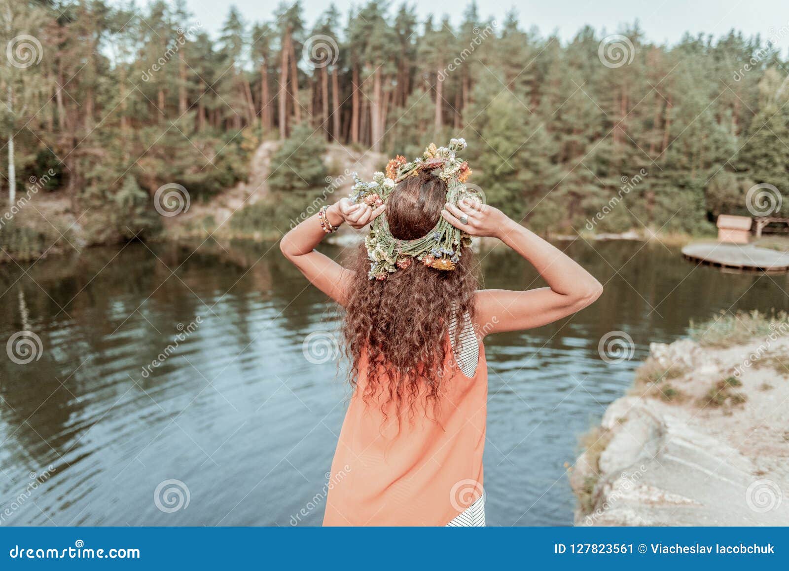 Curly Dark Haired Woman Wearing Orange Dress And Floral Chaplet