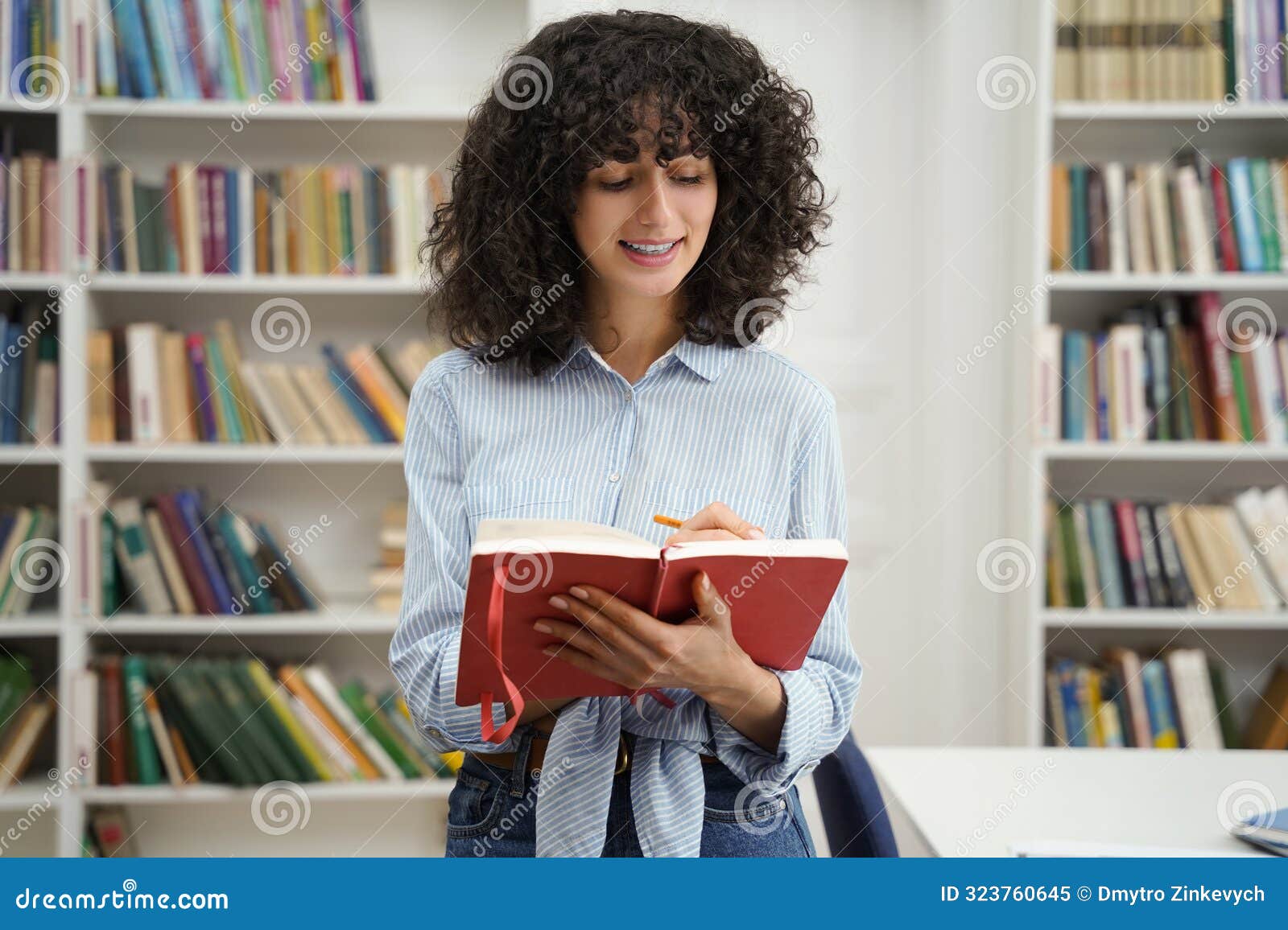 Curly-haired Woman Standing in the Library with a Book in Hands Stock ...