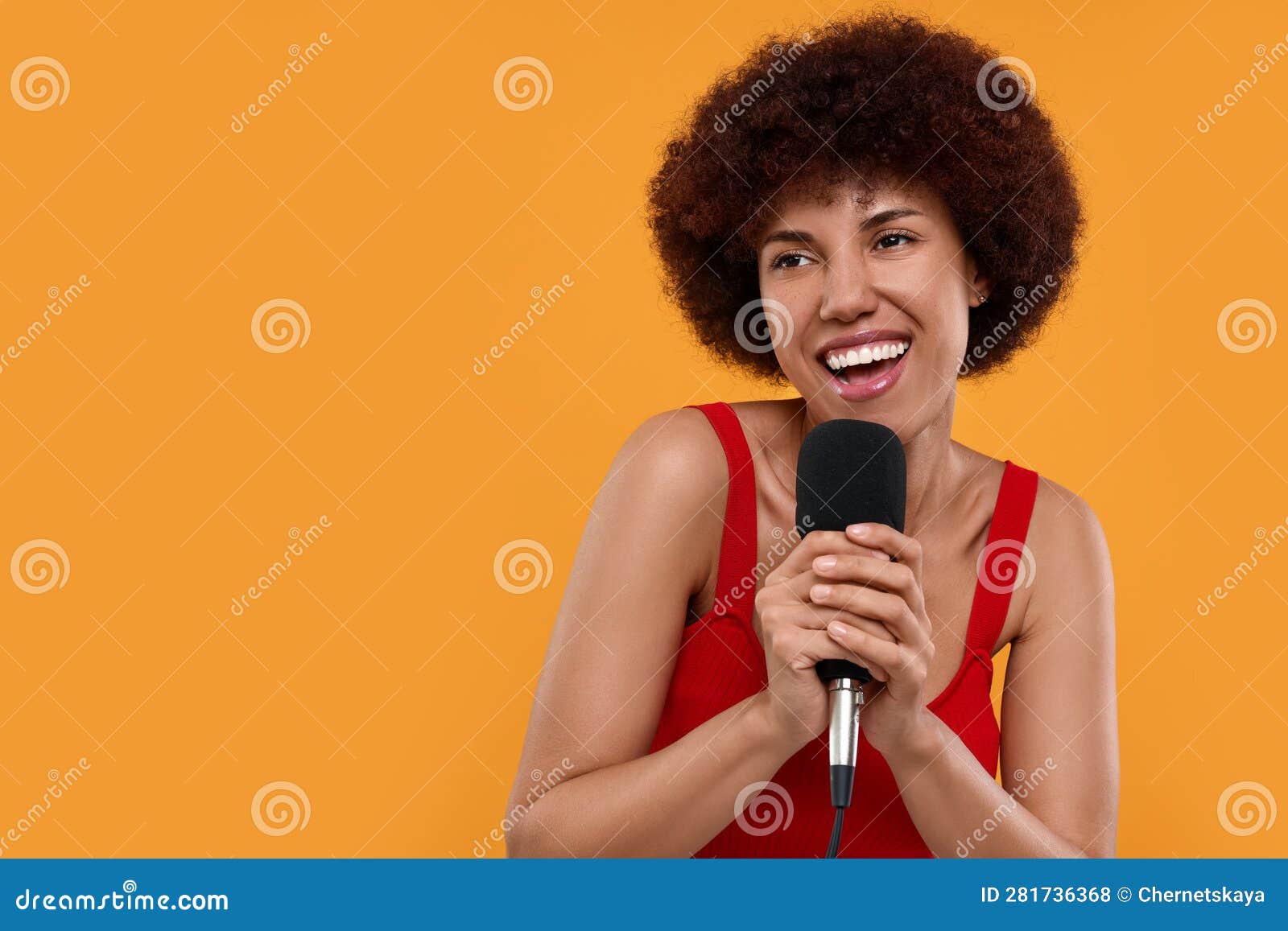 Curly Young Woman with Microphone Singing on Yellow Background, Space ...