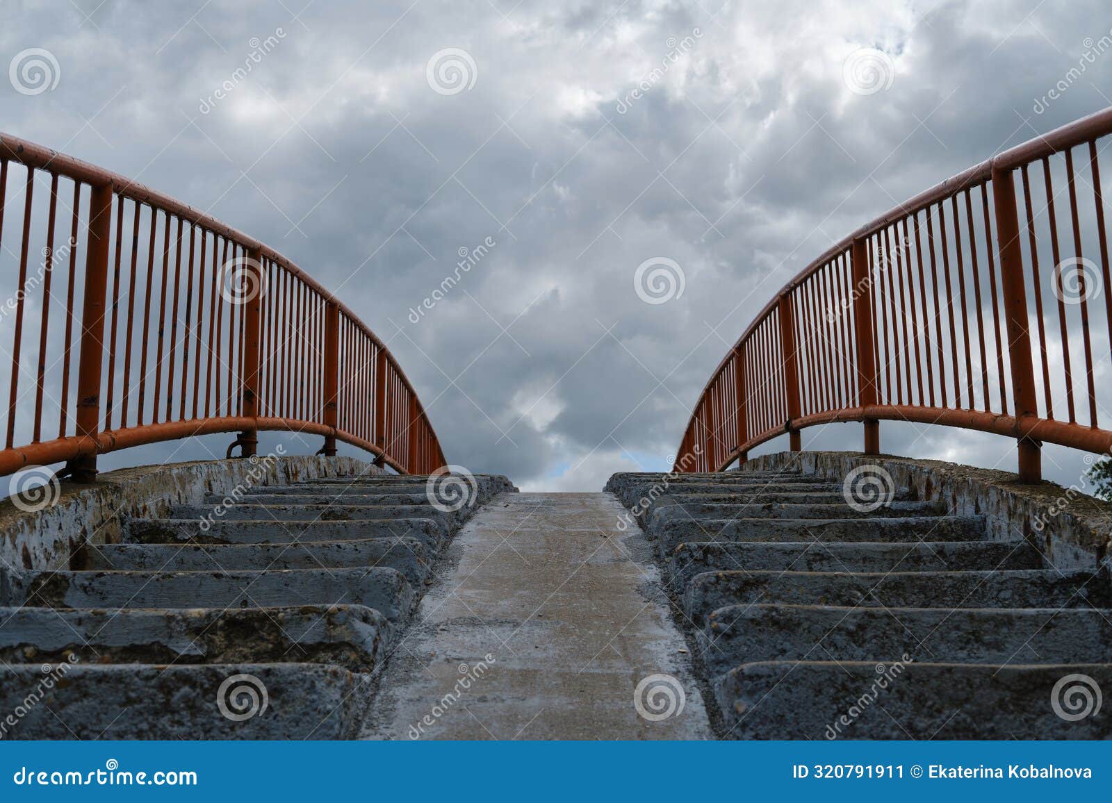 Curved Concrete Pedestrian Arch Bridge with Red Iron Railings with ...