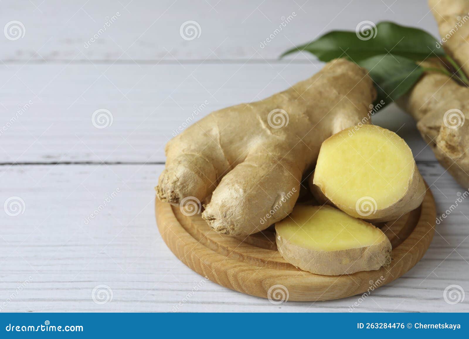 Cut and Whole Fresh Ginger with Leaves on White Wooden Table. Space for ...
