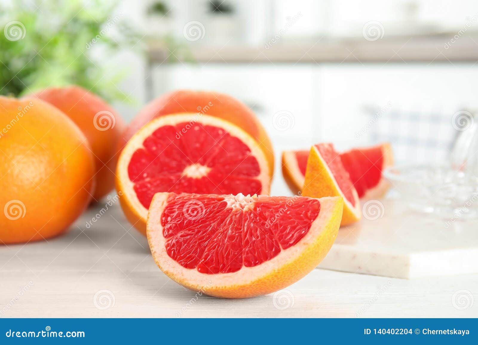Cut And Whole Grapefruits On Table Against Blurred Stock Photo - Image ...