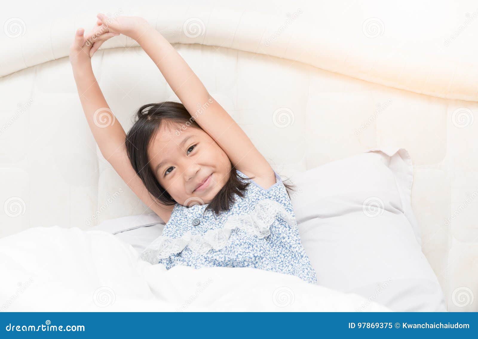 Cute Asian Girl In Pajamas Is Sitting On Bed Stretching Stock Image