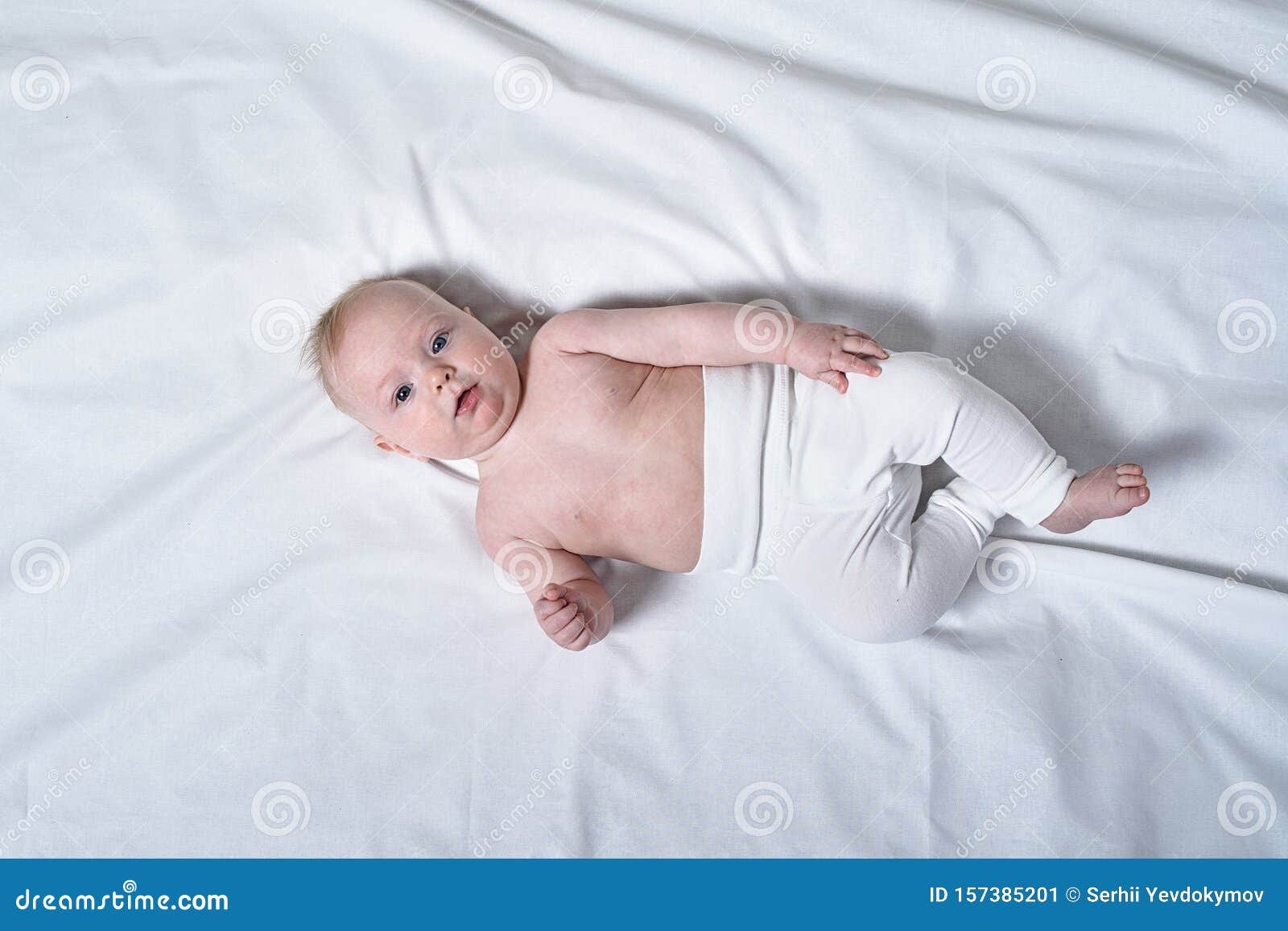 Cute Blond Baby with a Torso Lying on White Sheets. Top View Stock ...