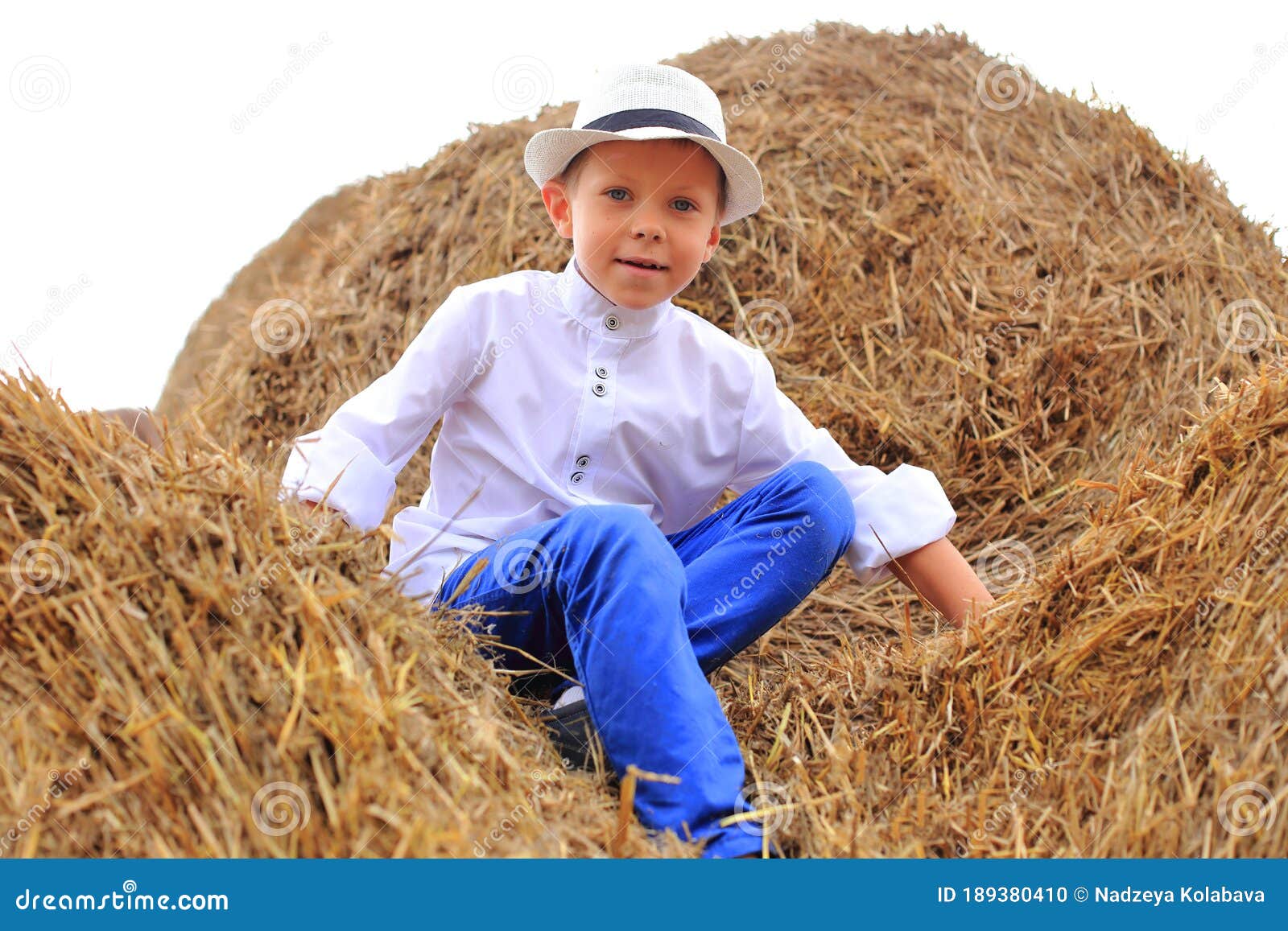 A Cute Boy is High Under the Sky on a Haystack in the Hay Season. Stock ...