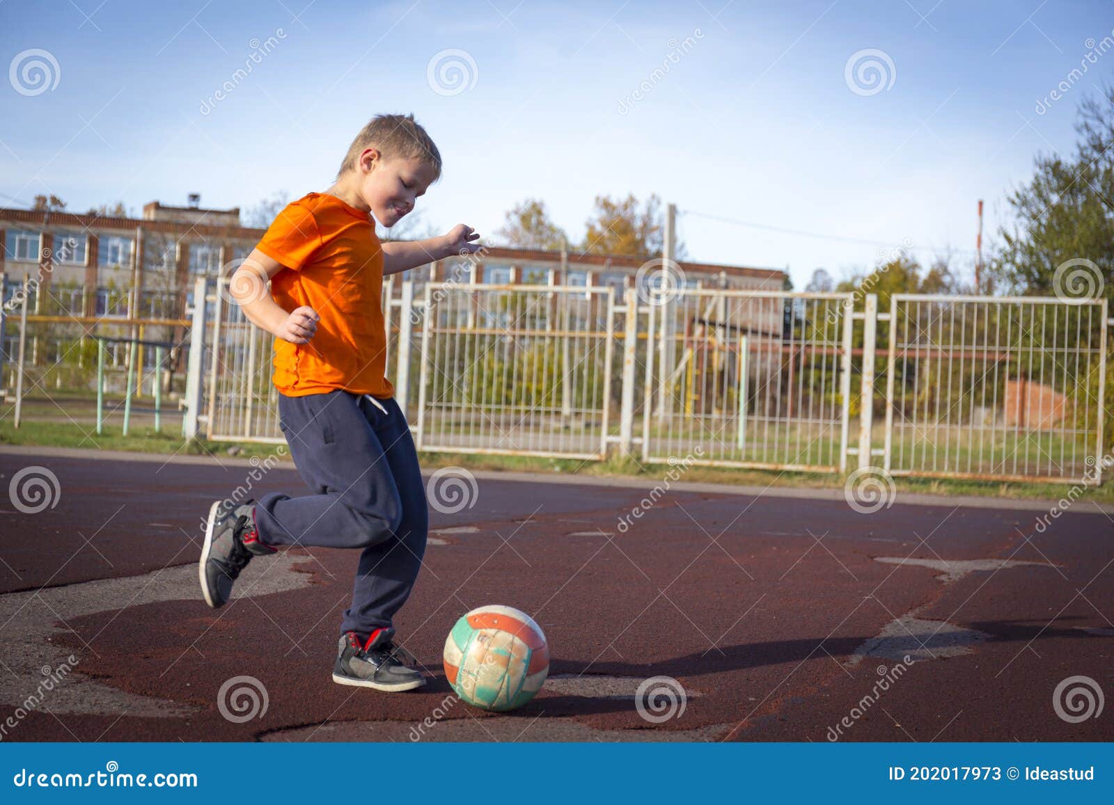 Cute Boy Kicking the Ball on City Playground. Stock Image - Image of ...
