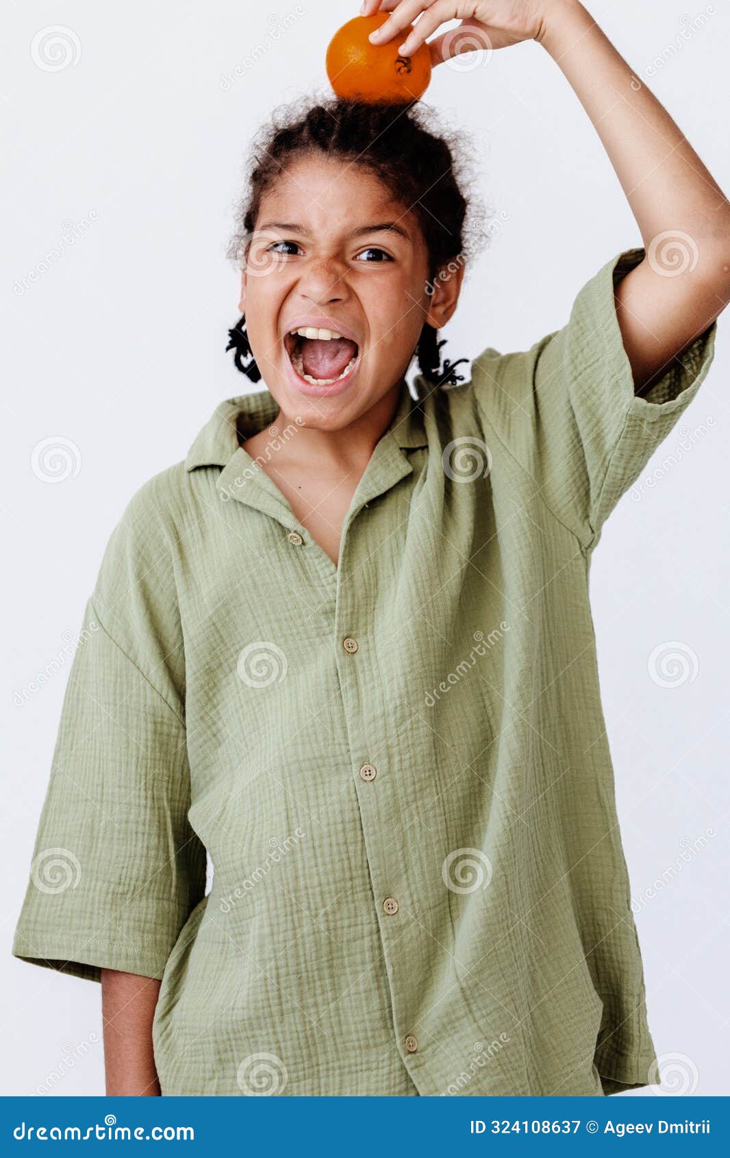 Adorable Young Boy Making a Silly Face while Holding an Orange Fruit in ...