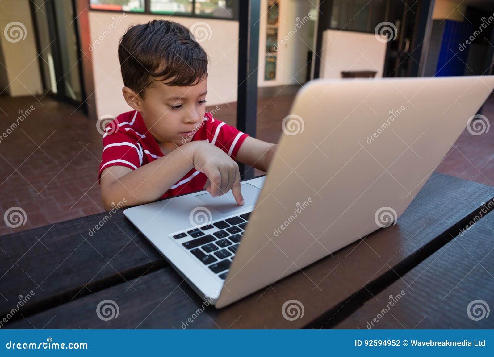 Cute Boy Working on Digital Laptop while Sitting at Table Stock Photo ...