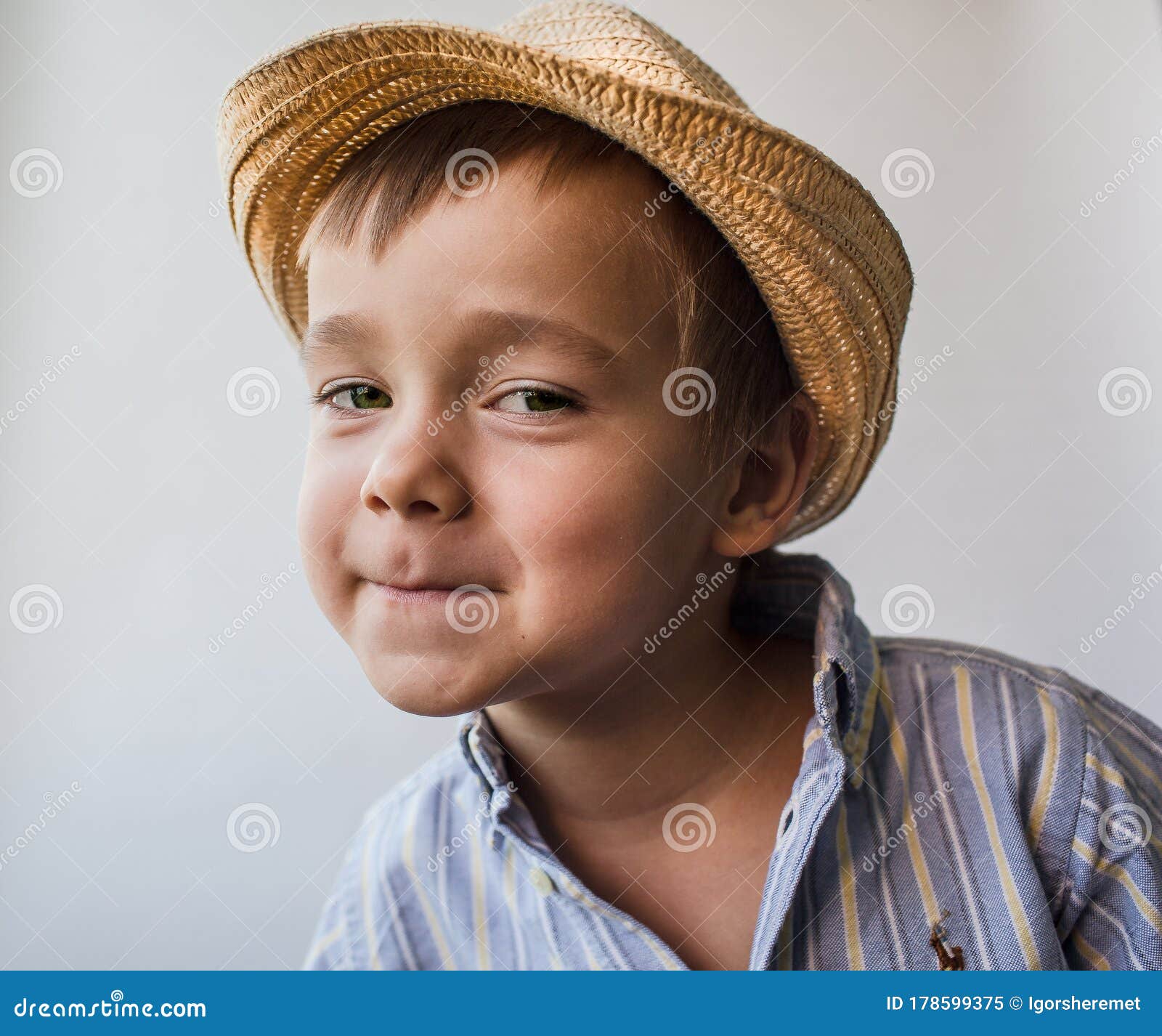 A Cute Child in a Straw Hat Looks Slyly into the Frame on a White ...