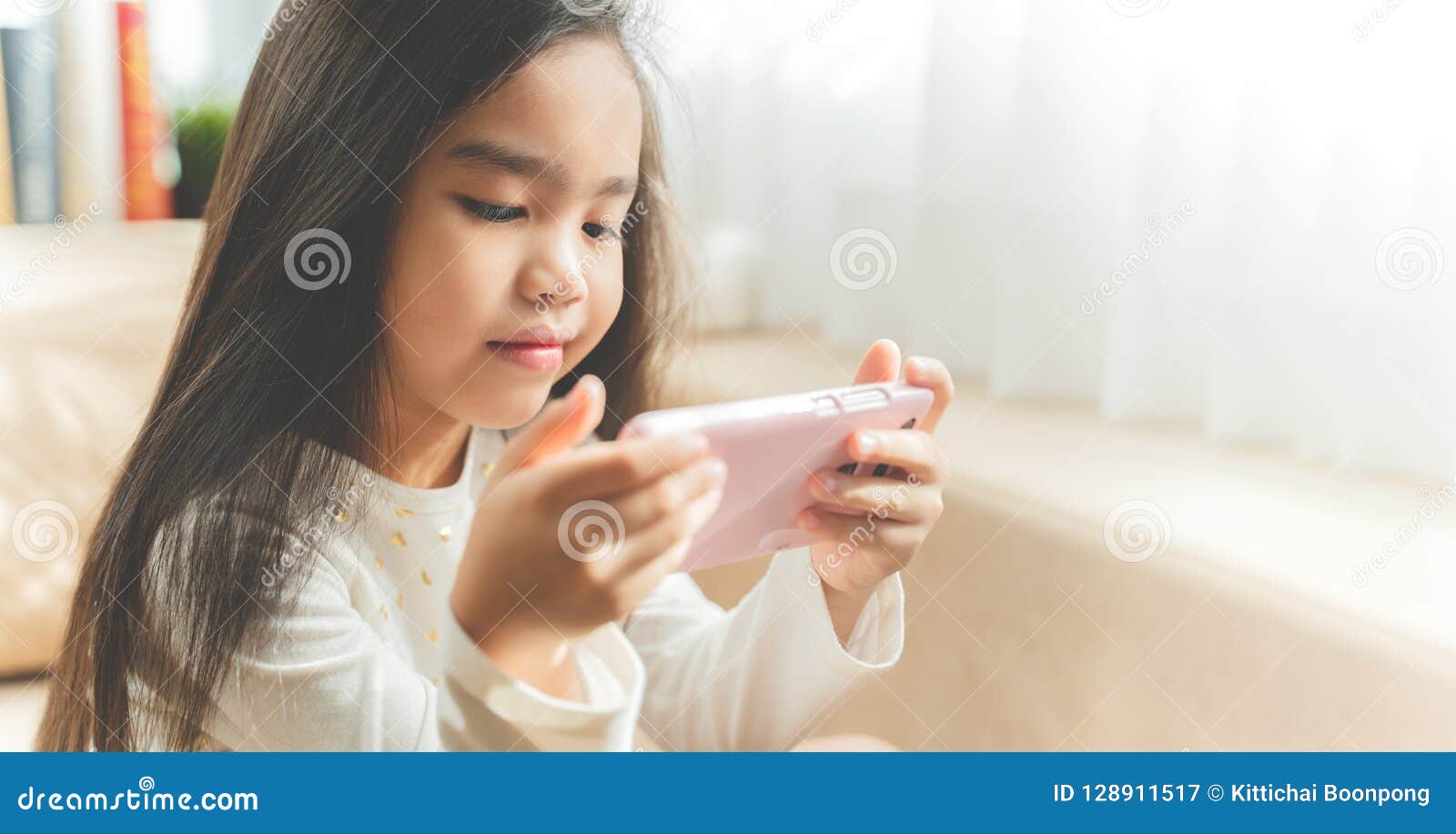 Cute Child Using a Smartphone and Smiling while Sitting on Sofa Stock ...