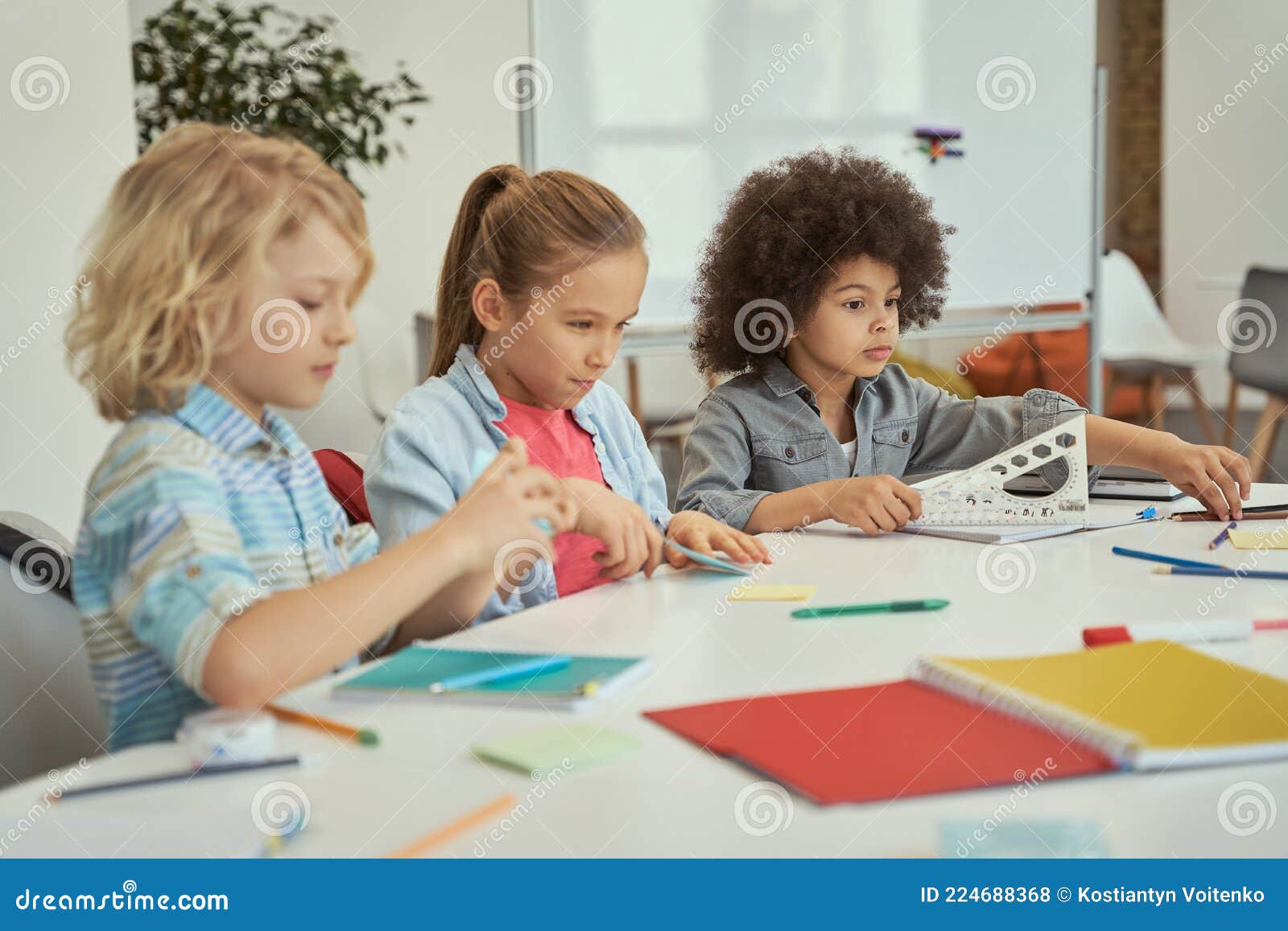 Cute Diverse Kids Sitting Together at the Table while Studying in ...