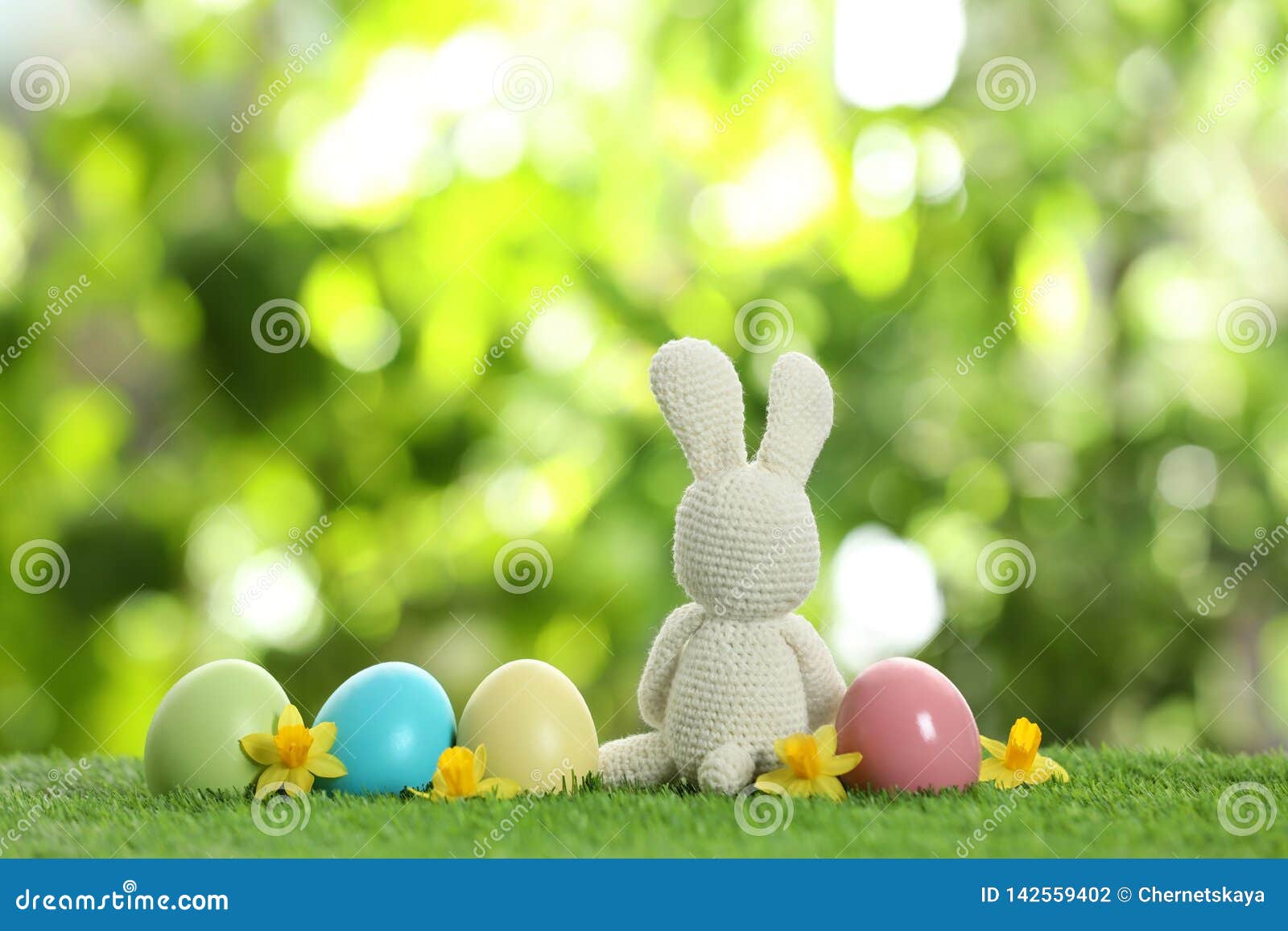 Cute Easter Bunny Toy and Dyed Eggs on Green Grass Against Blurred ...