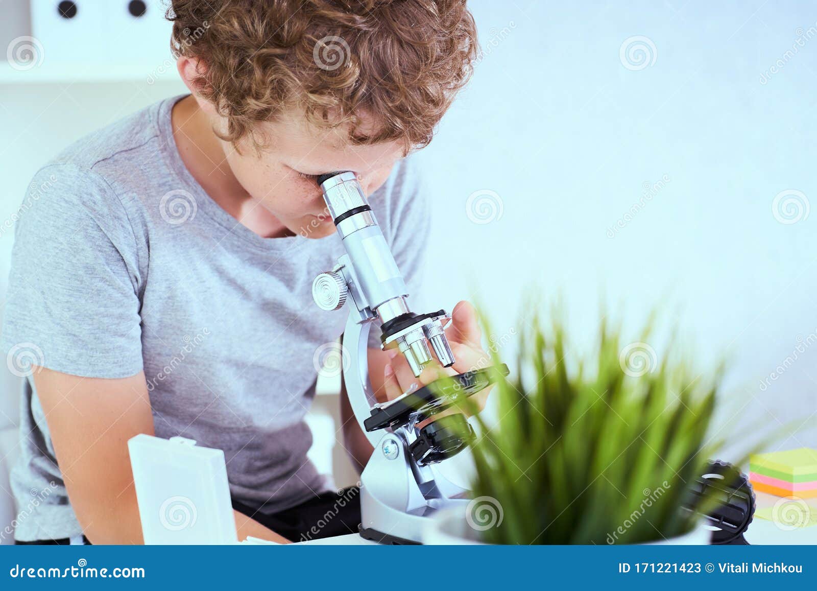 Cute Elementary Schoolboy Looking into Microscope at His Desk in the ...