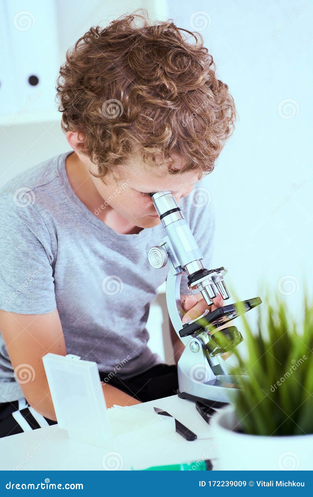 Cute Elementary Schoolboy Looking into Microscope at His Desk in the ...