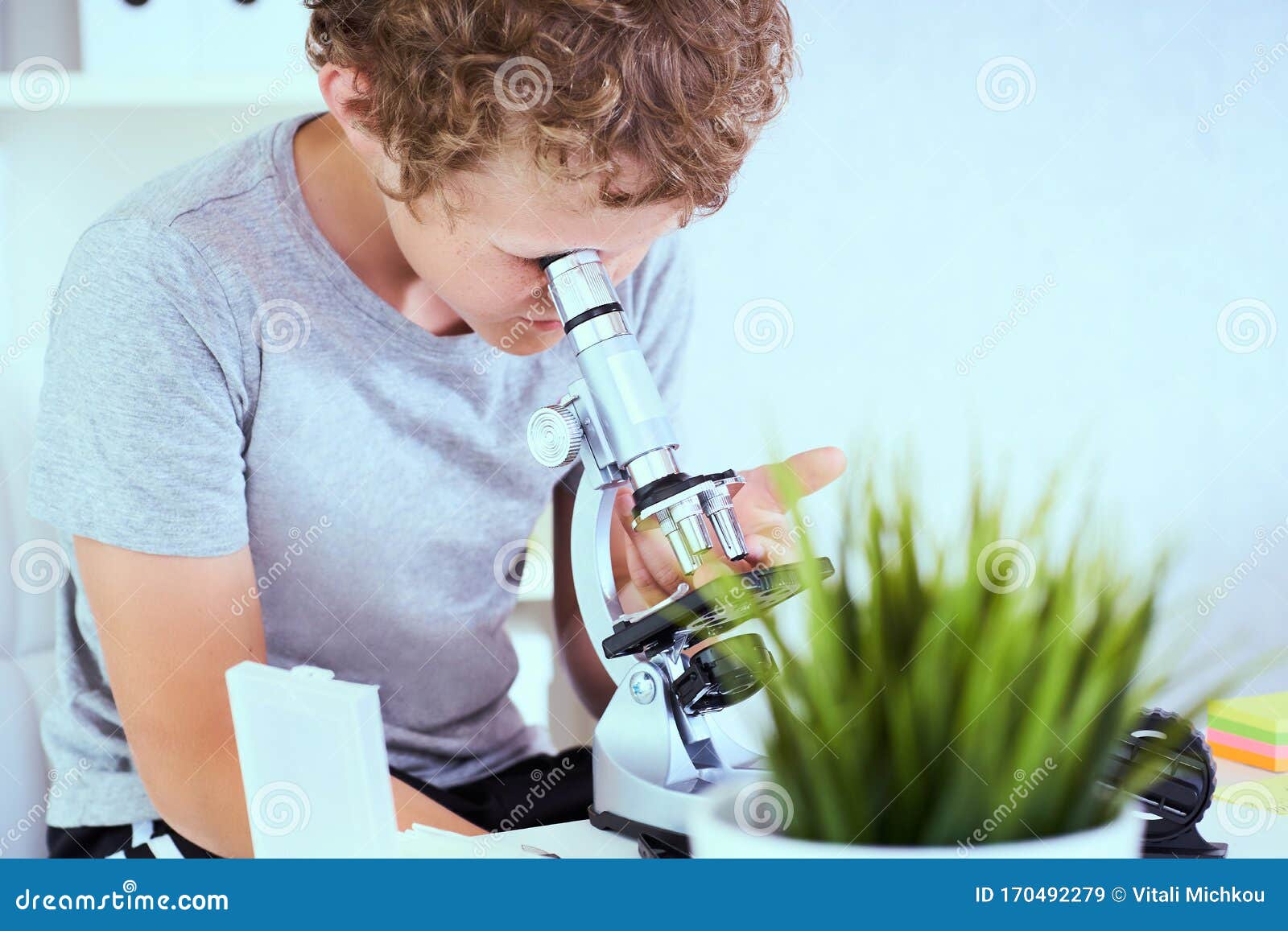 Cute Elementary Schoolboy Looking into Microscope at His Desk in the ...