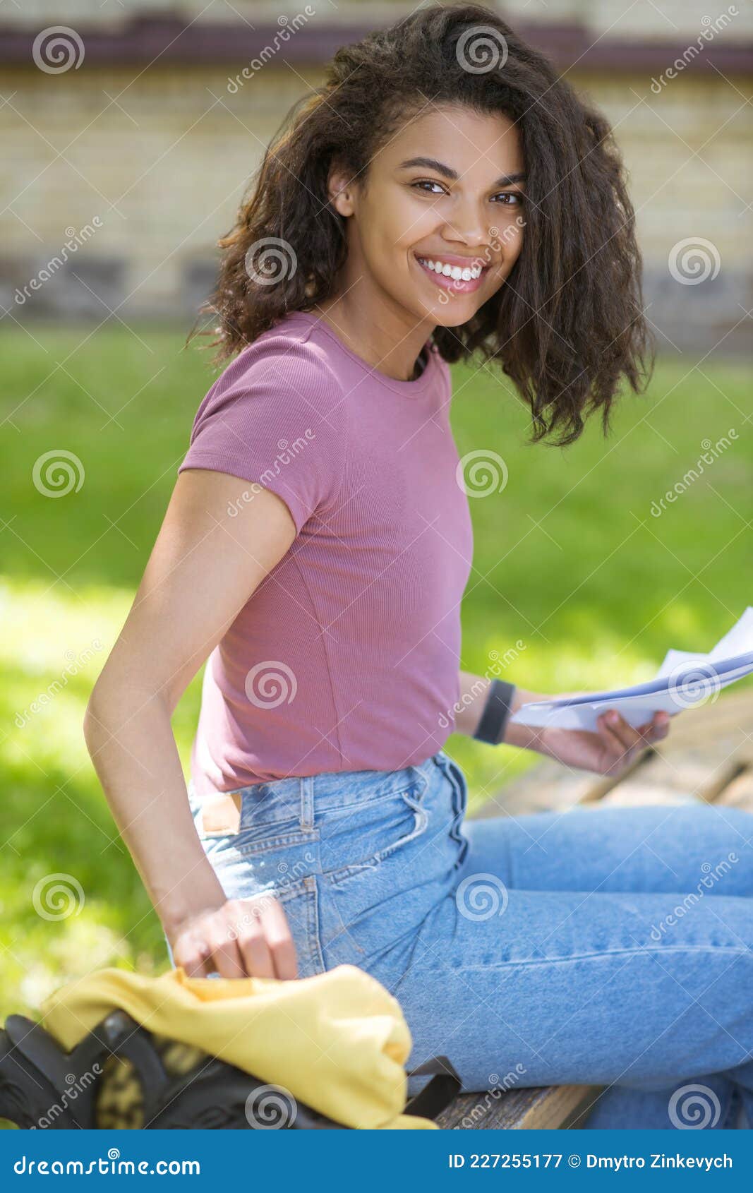 A Cute Girl In A Pink Tshirt Sitting On The Grass In The Park Stock