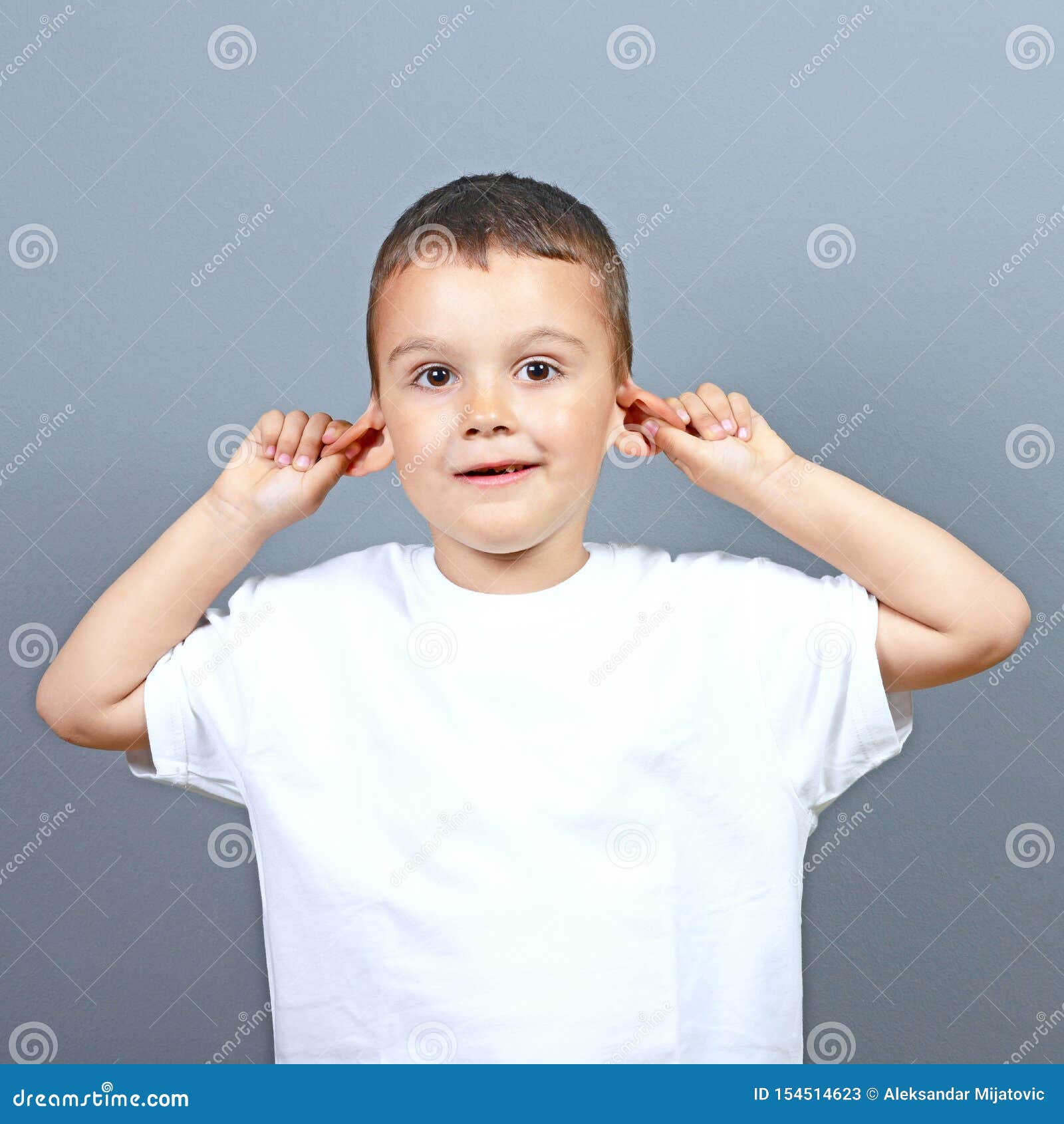 Cute Little Boy Kid Making Funny Face and Pulling Ears Against Gray ...