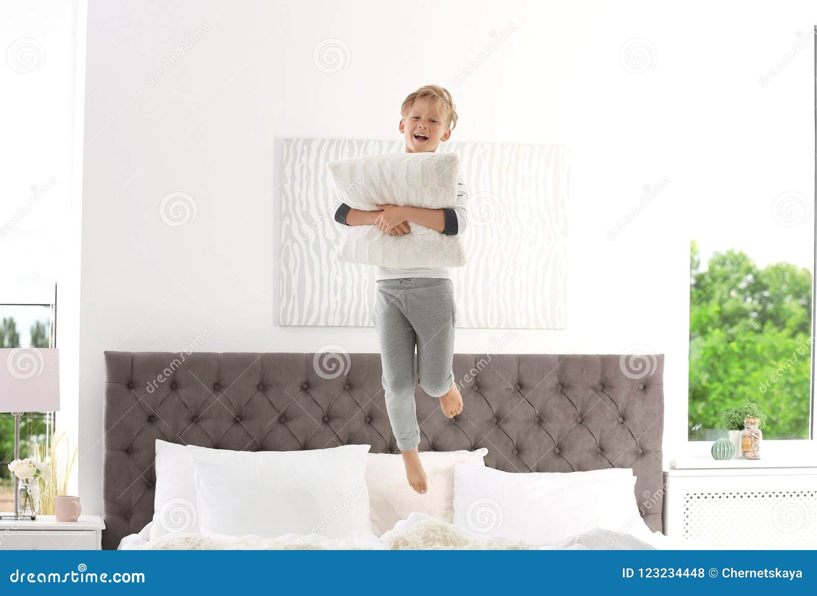 Cute Little Boy with Pillow Jumping on Bed Stock Photo - Image of ...