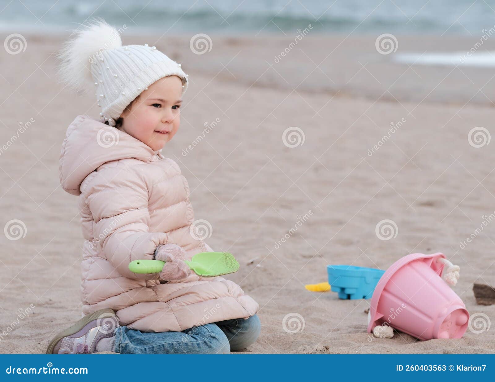 Cute Little Girl is Digging in the Sand on a Cold Day at the Beach ...