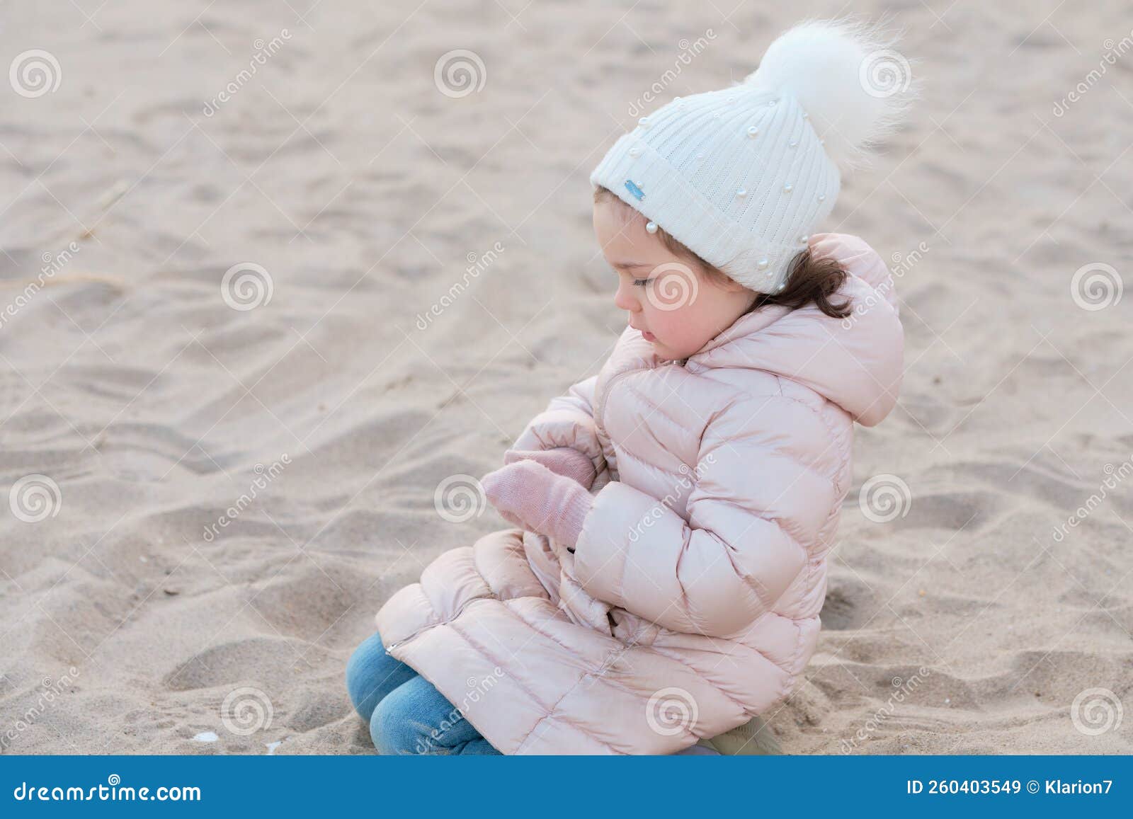 Cute Little Girl is Digging in the Sand on a Cold Day at the Beach ...