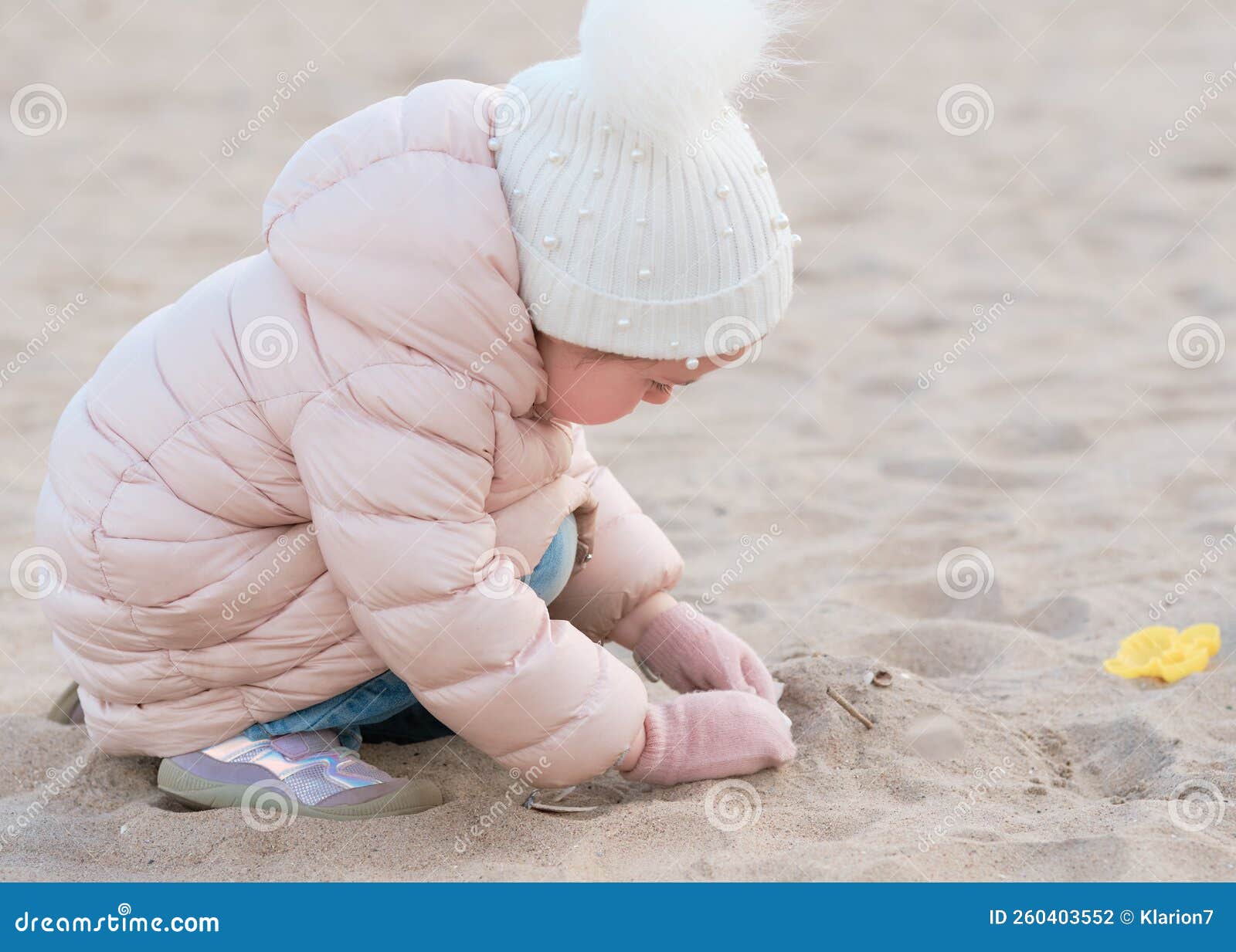 Cute Little Girl is Digging in the Sand on a Cold Day at the Beach ...