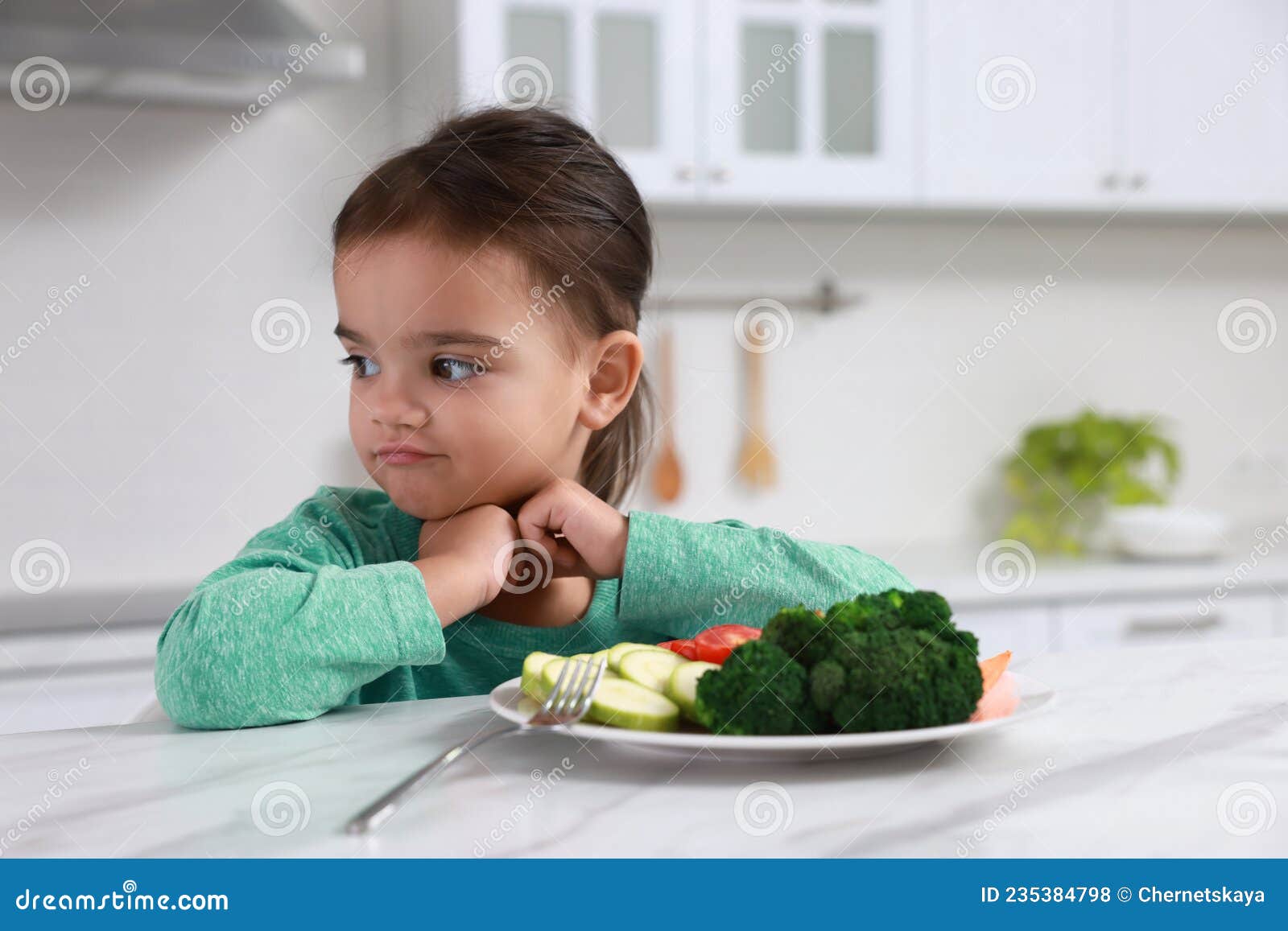 Cute Little Girl Refusing To Eat Vegetables in Kitchen Stock Photo ...